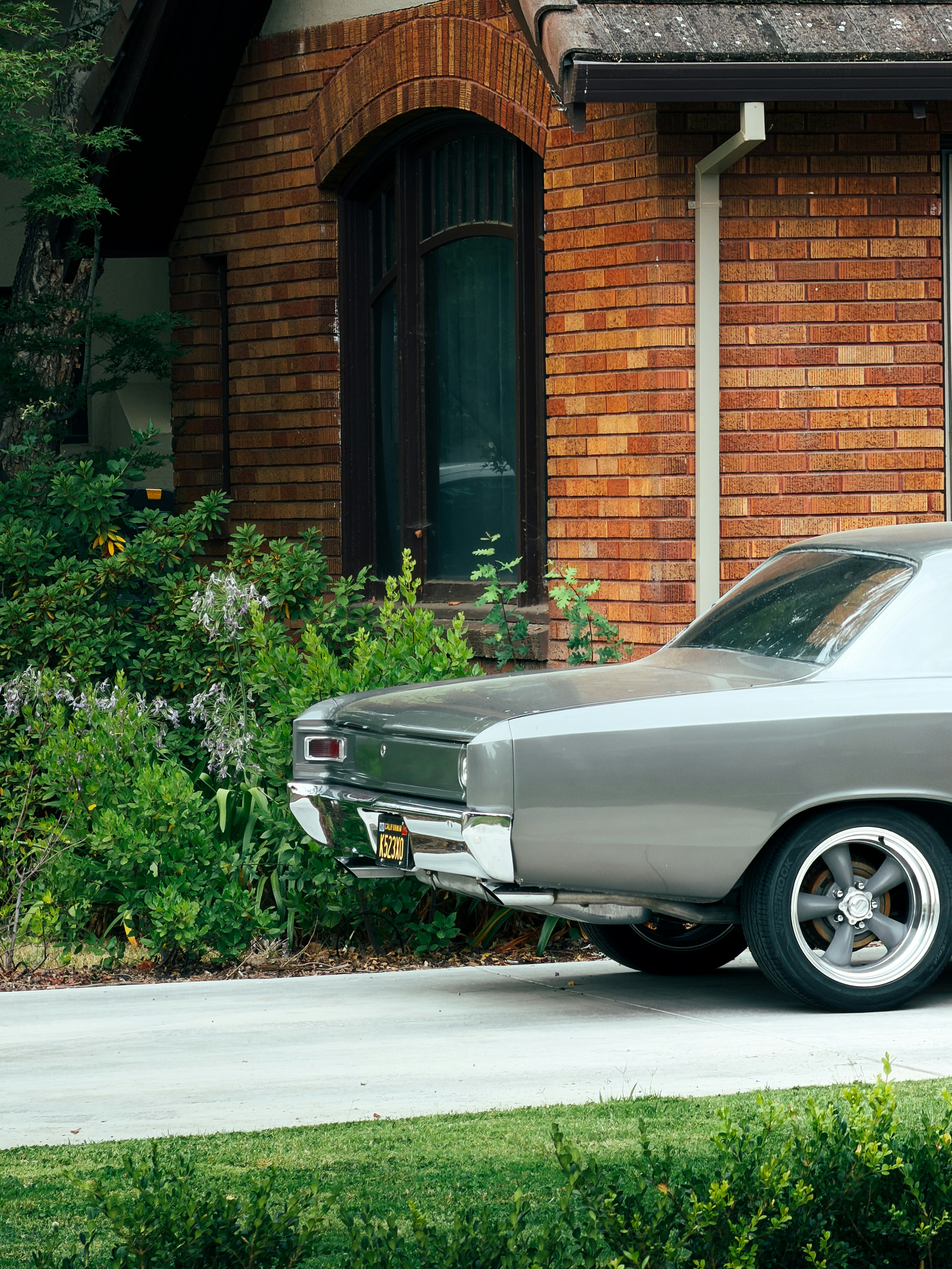 Silver Classic by the Driveway: A Brick Facade and Chrome Car