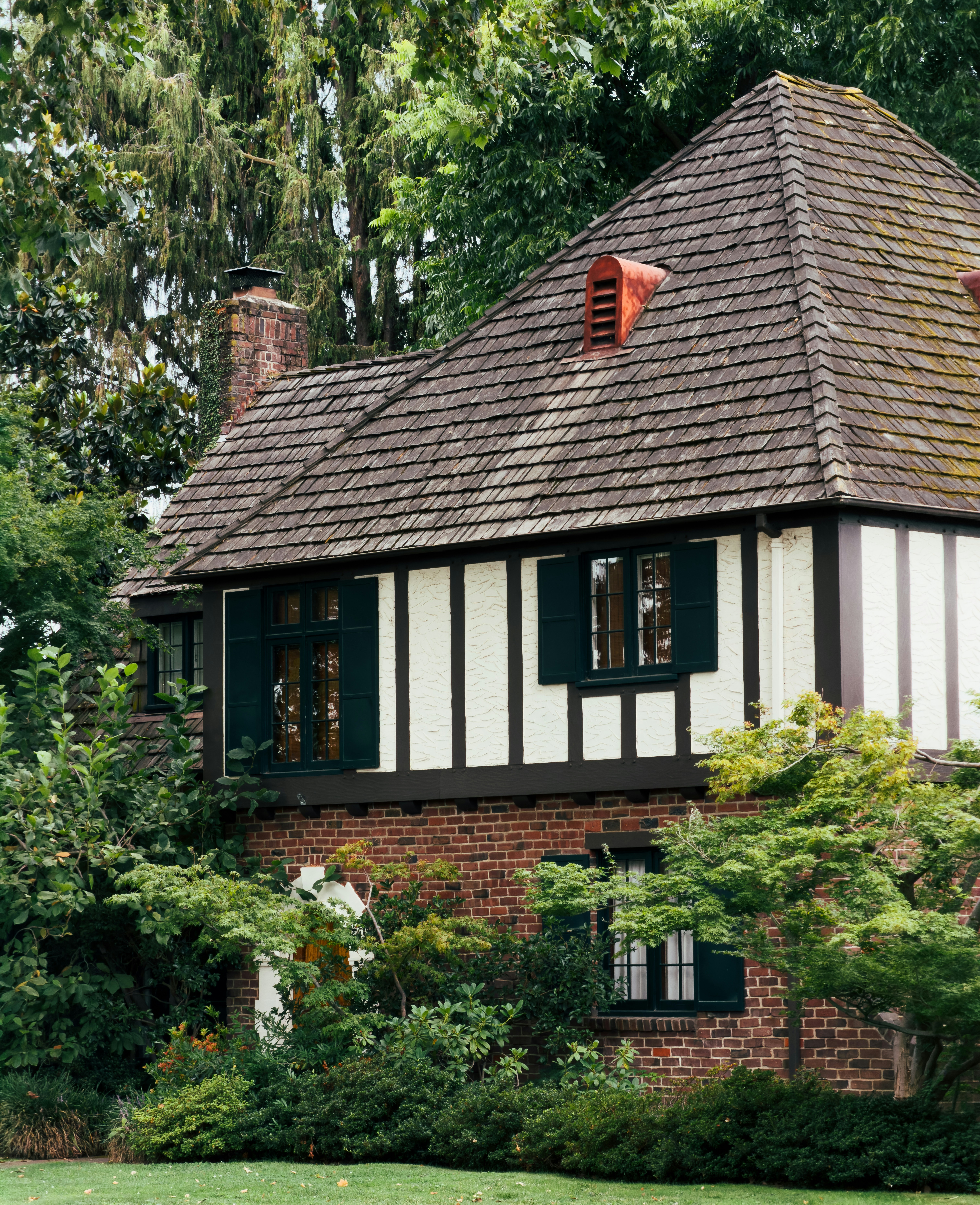 Timbered Cottage Under a Shingled Roof Framed by Greenery