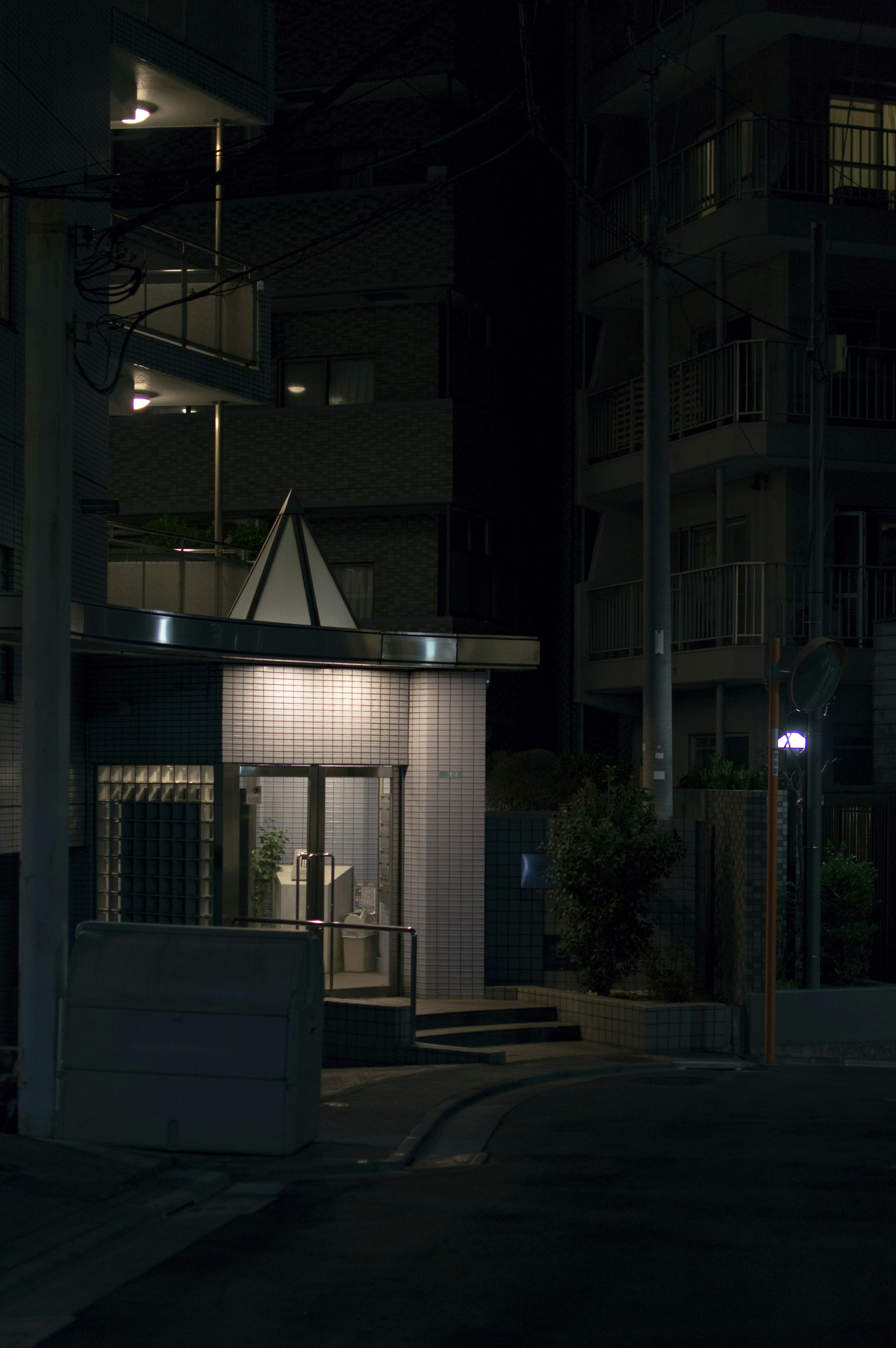 Night Entrance: Quiet Neon Light Illuminates a Tiled Lobby Below a Concrete Structure