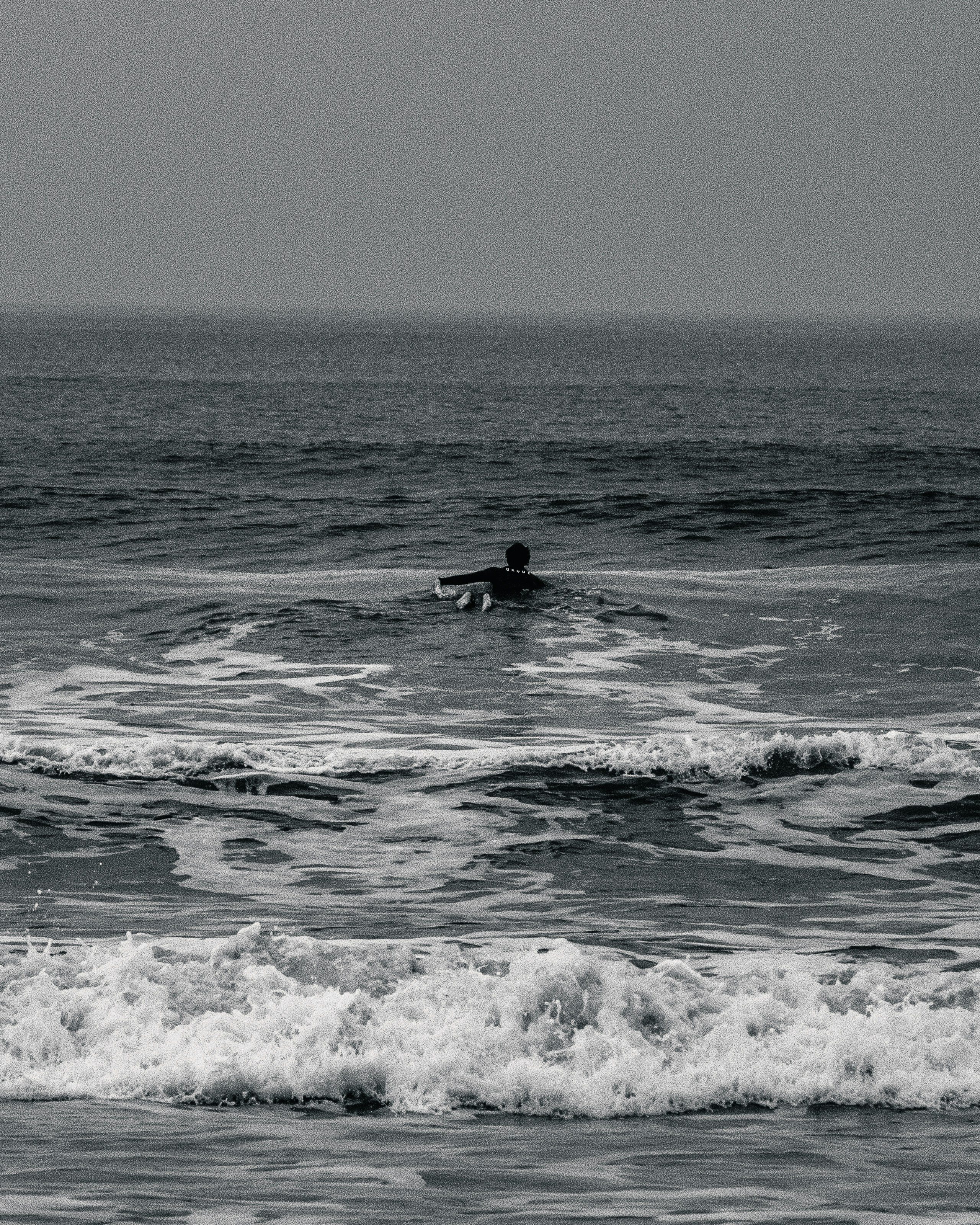 Somber Swell: A lone surfer rides a quiet horizon