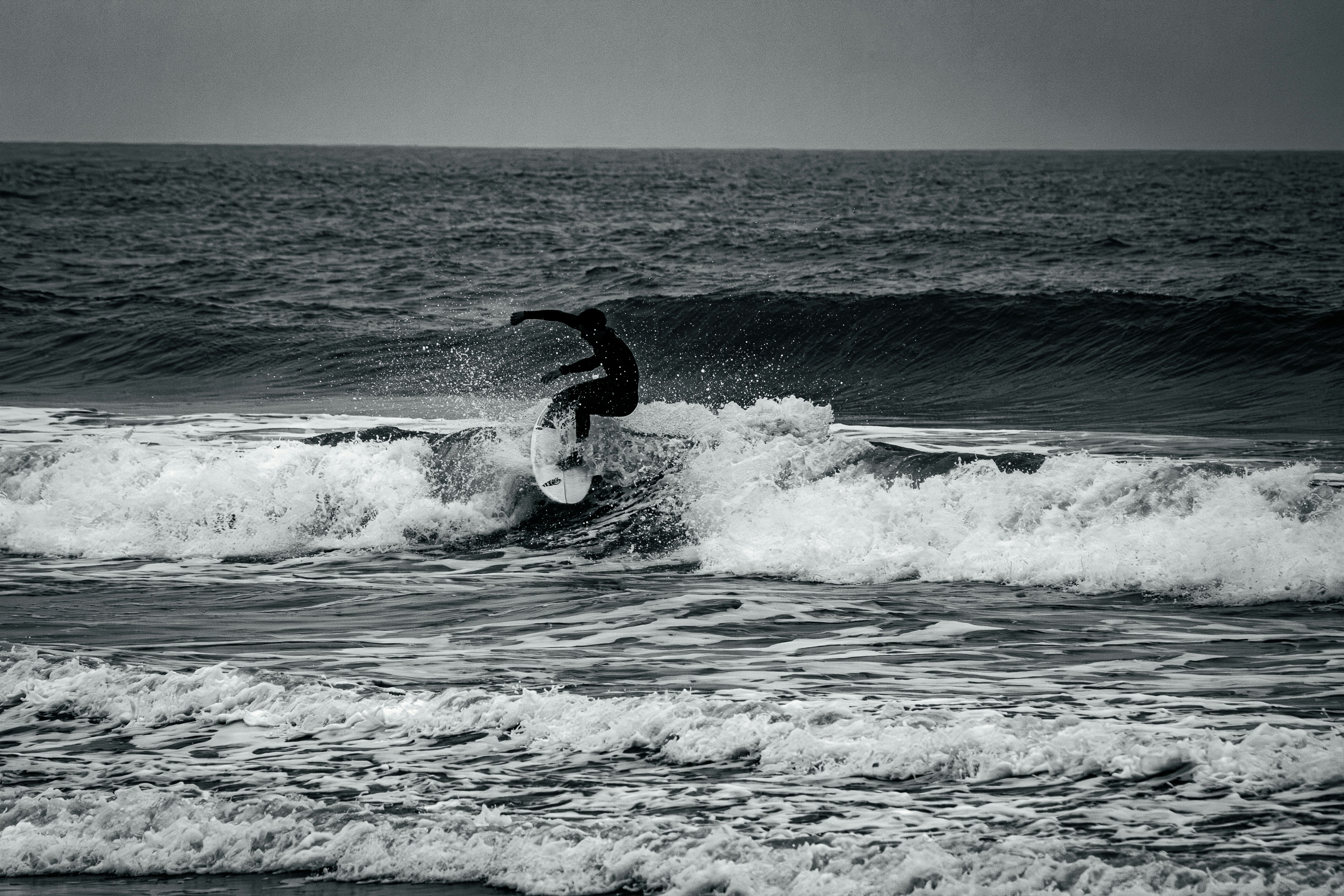 Coiled Crest: A surfer’s moment rider on a monochrome ocean