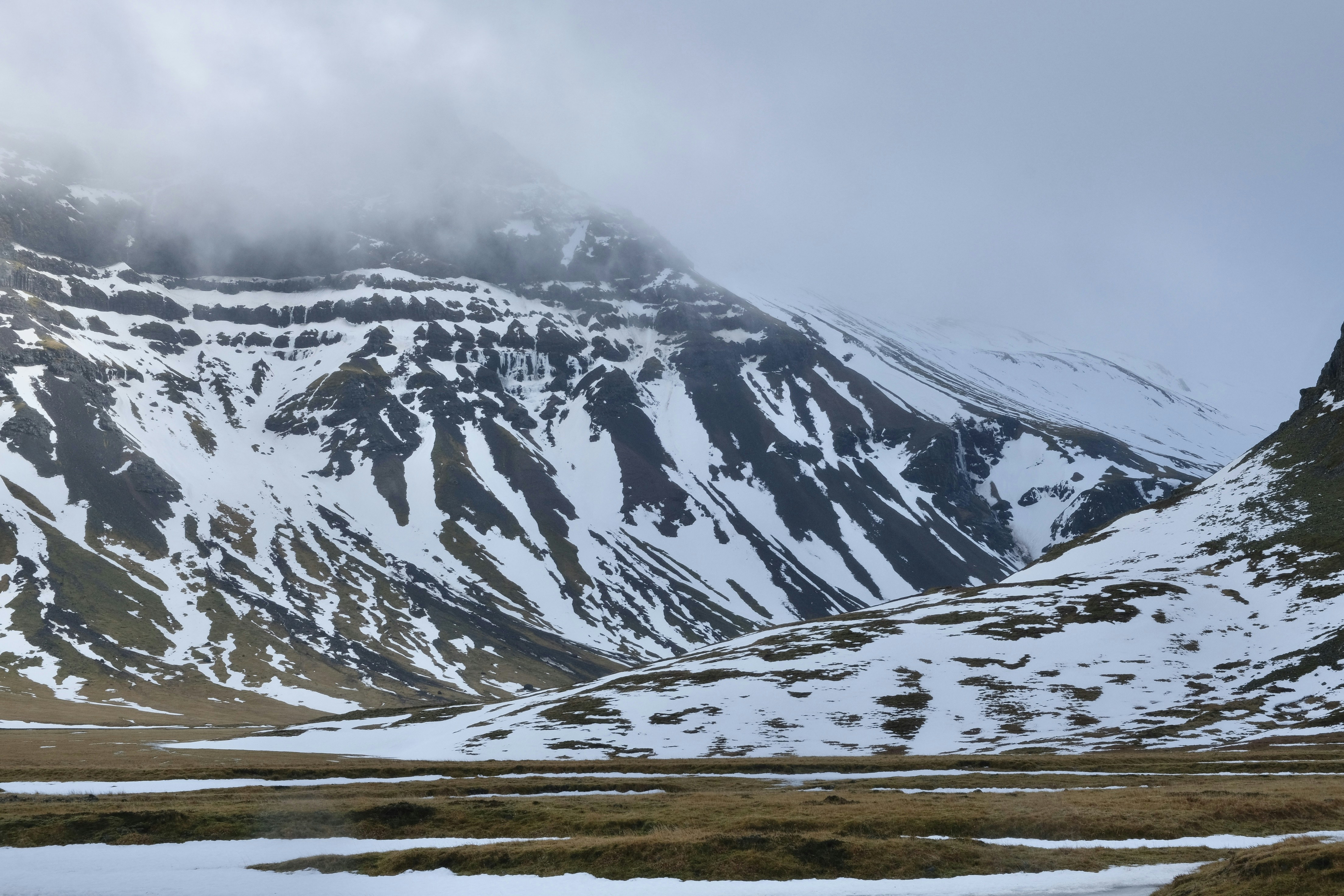 Snow-Capped Ridge Under Clouded Sky