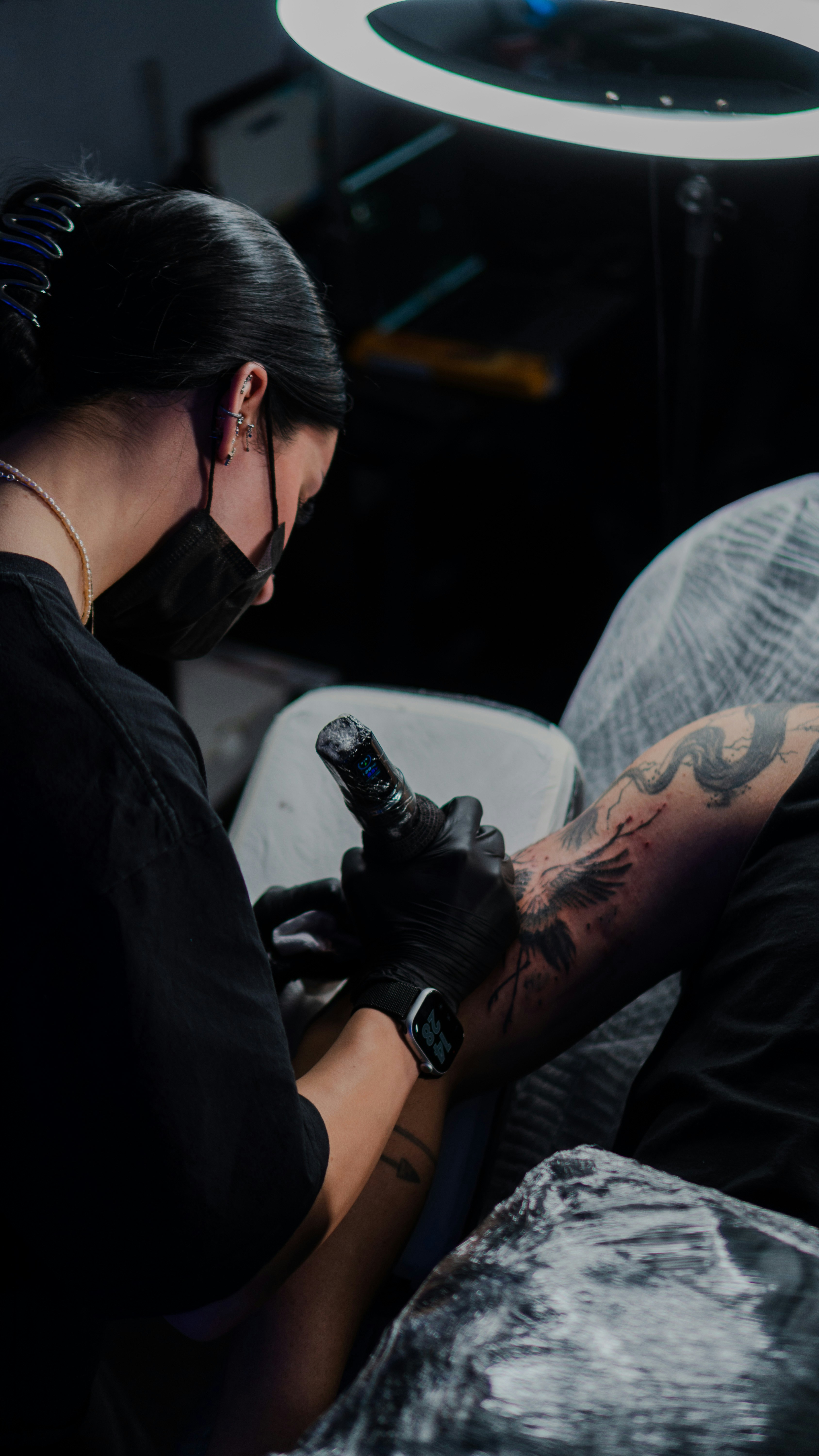 Inked Focus: Tattoo Artist at Work under Ring Light