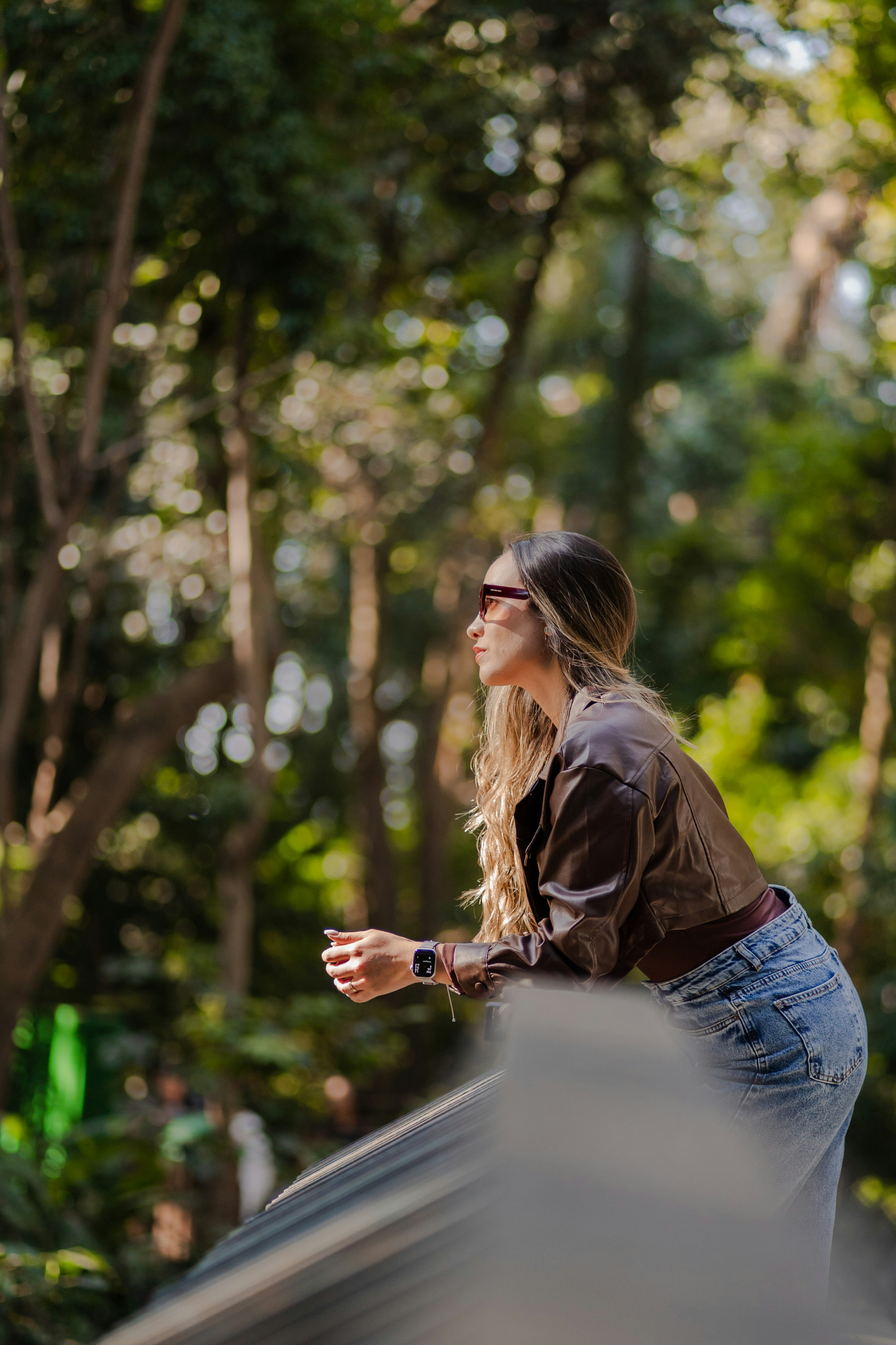 Young woman leaning on a railing in a park.