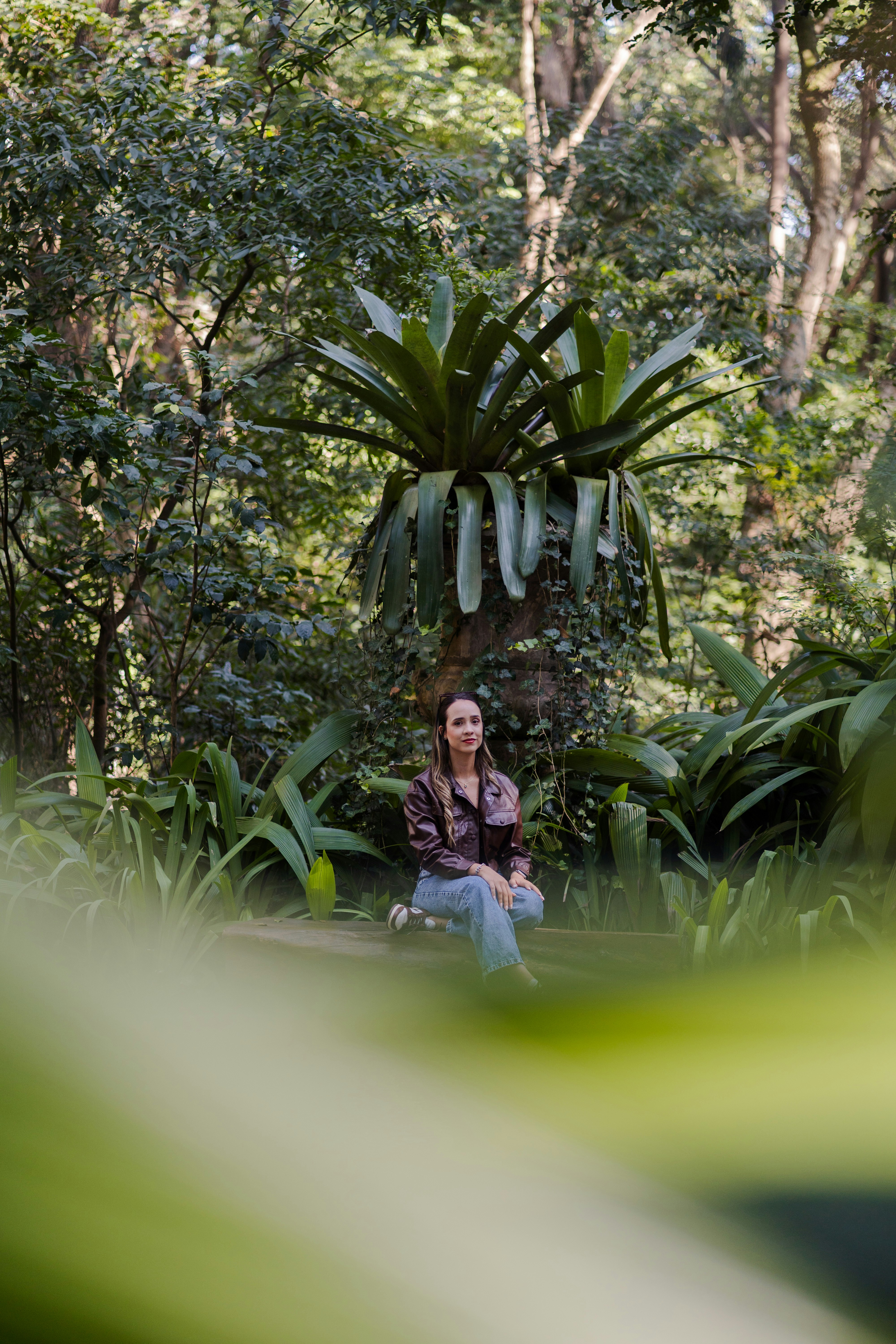 Woman in a Purple Jacket Settling Among Giant Tropical Leaves