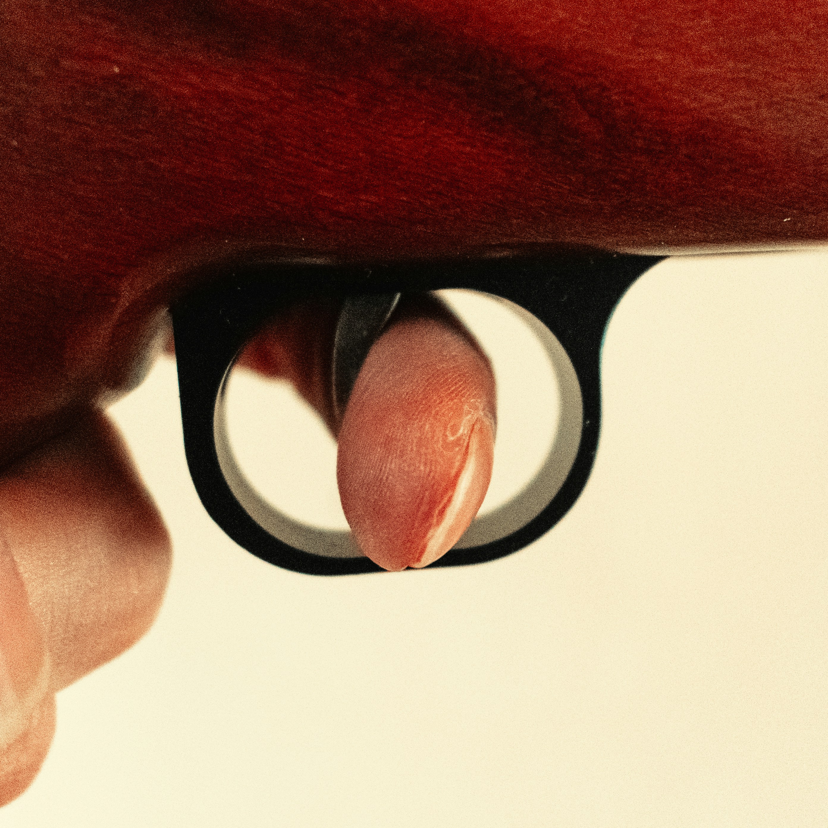 Close-up of a fingertip under a wooden object’s trigger guard