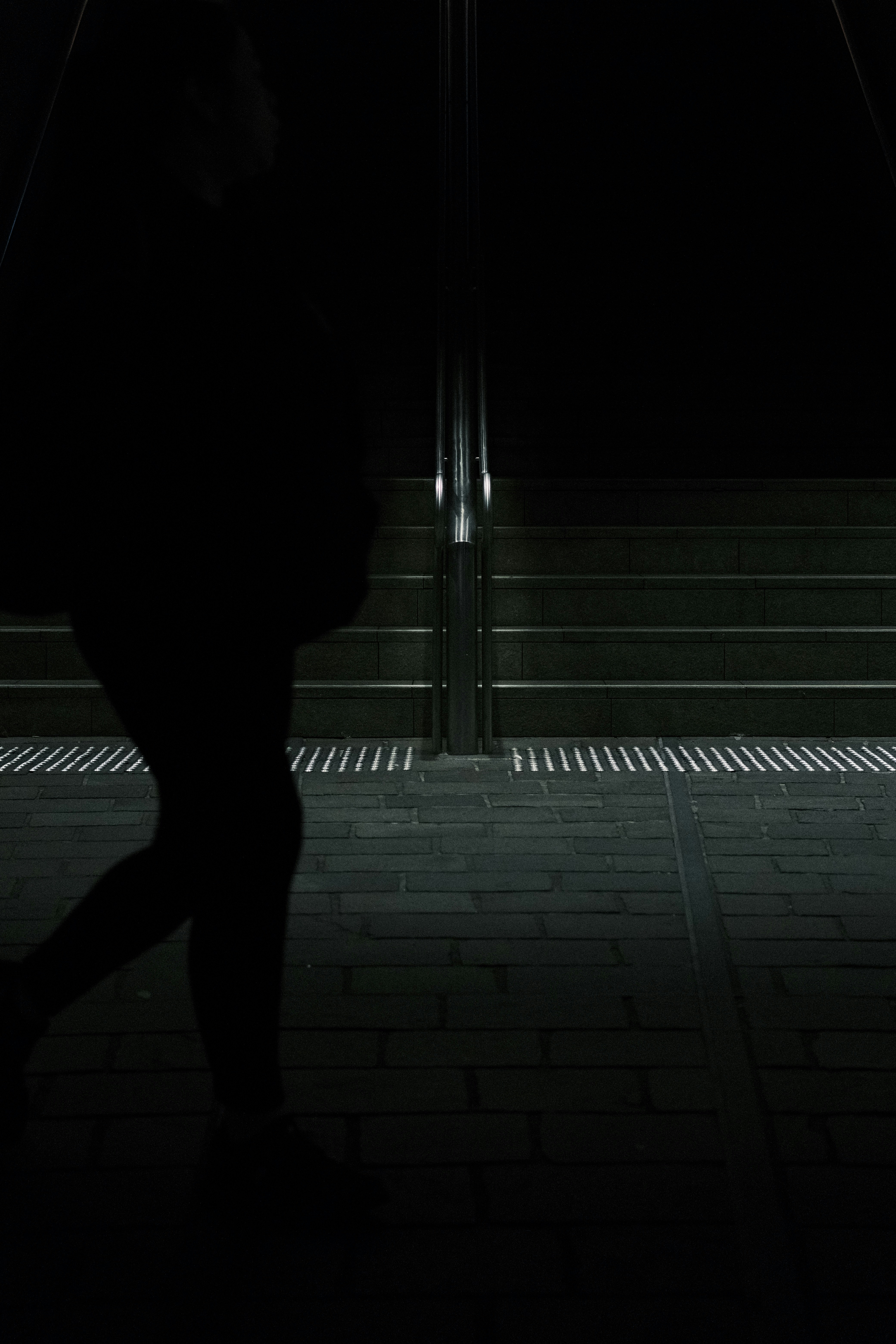 Silhouette on Steps: Night Pedestrian Crossing a Quiet City Threshold