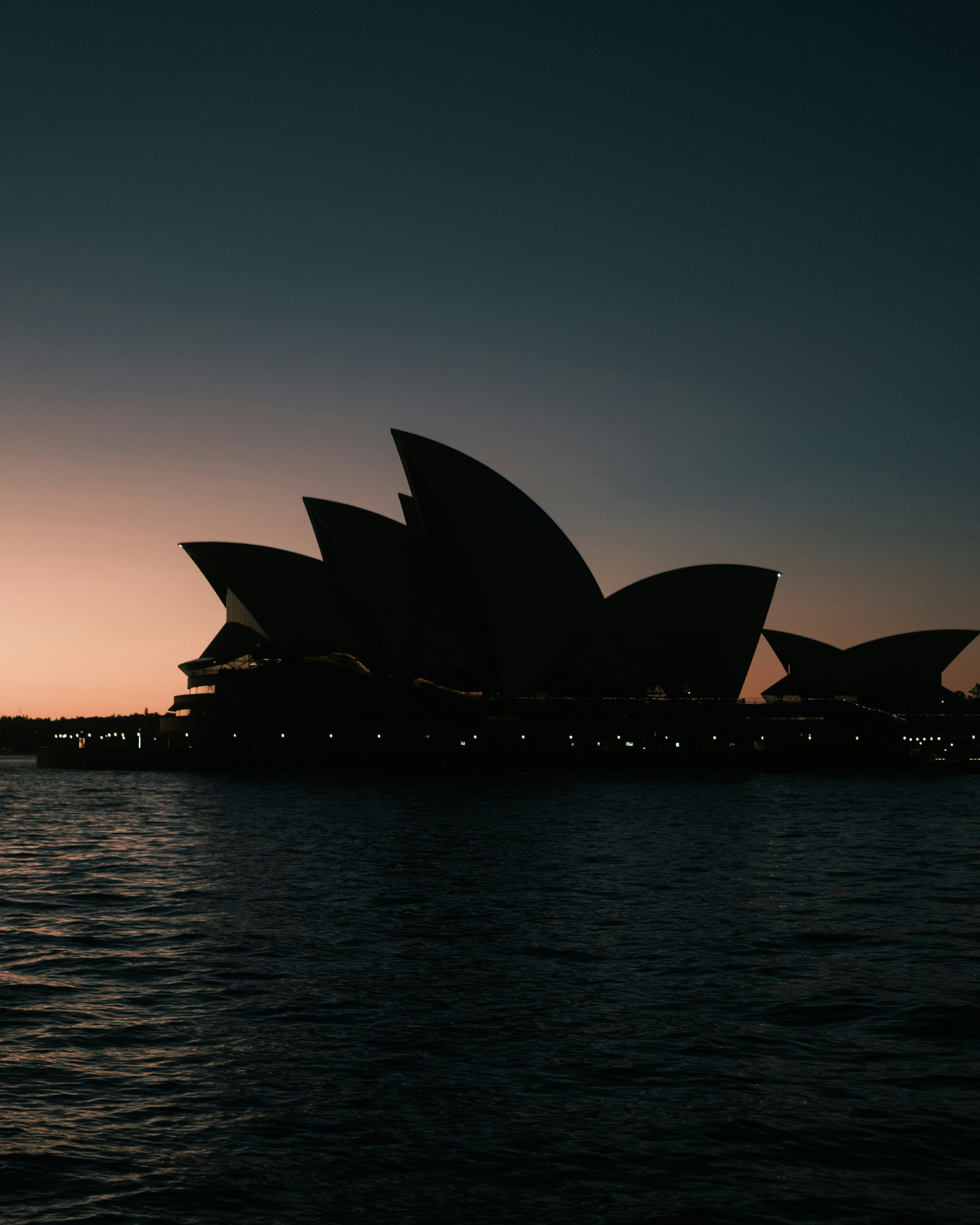 Silhouetted Opera House at Dusk over Quiet Harbour