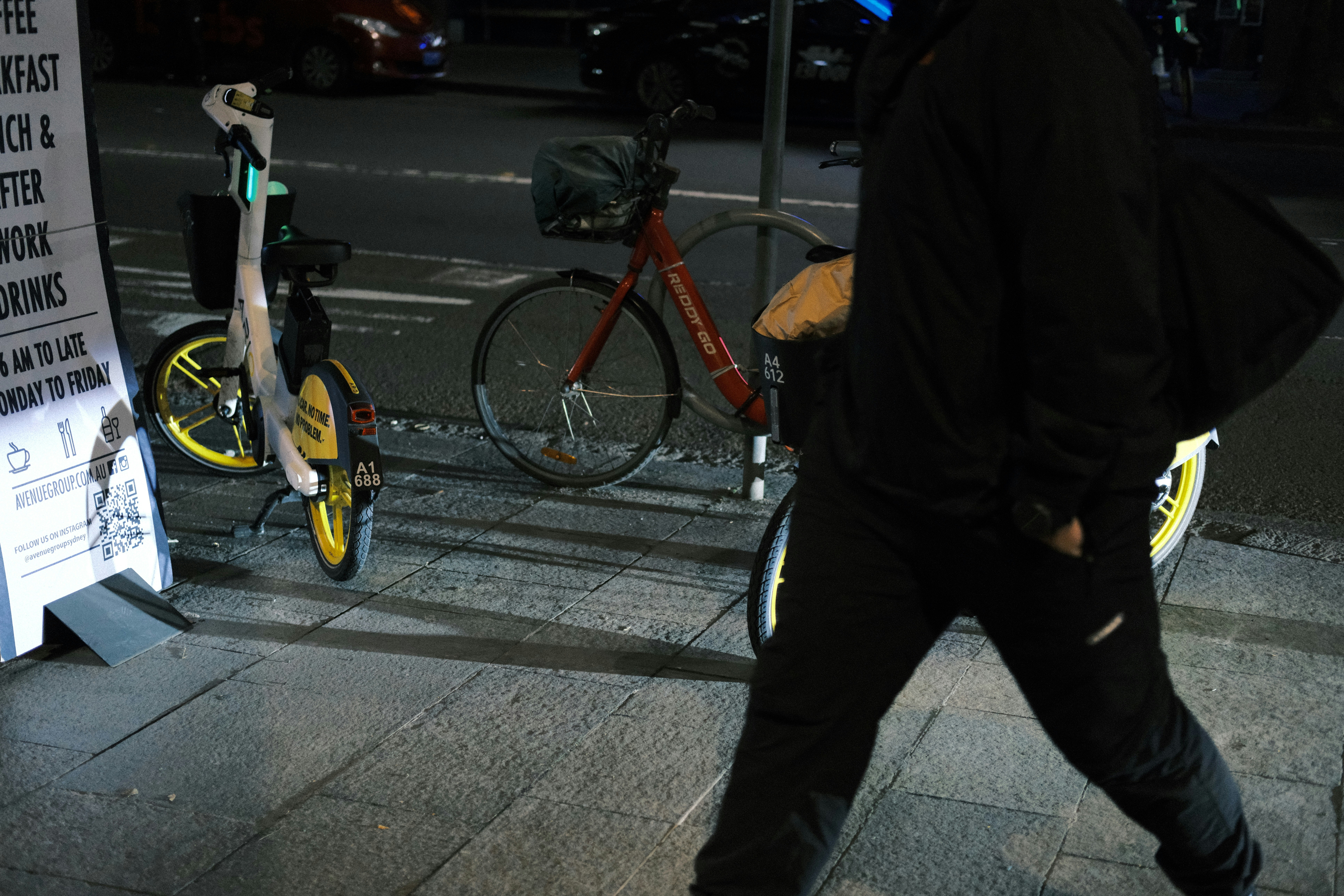 Night Street Portrait: A Pedestrian Walks Past Brightly Colored Bikes