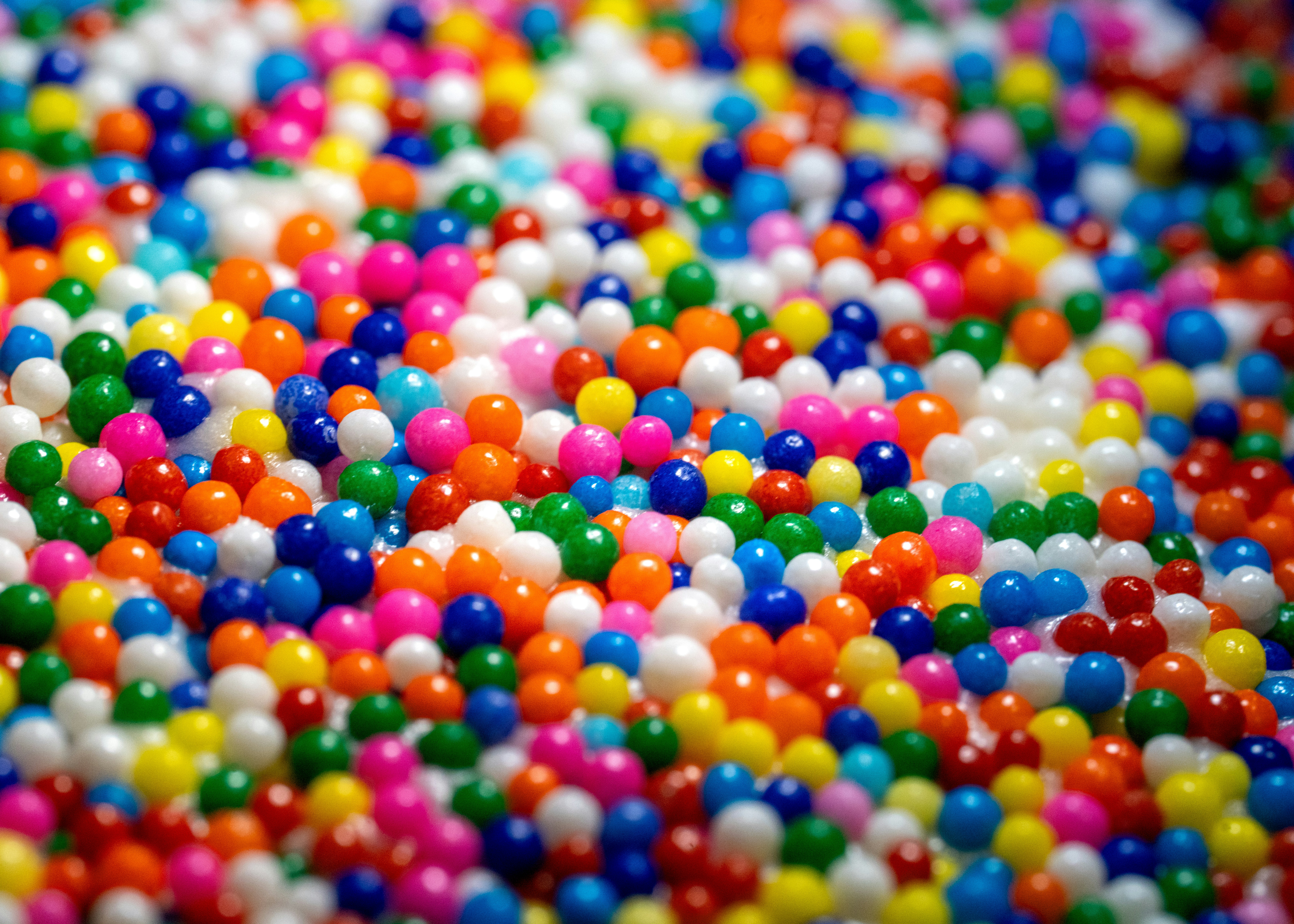 A dense field of multicolored plastic balls fills the frame, creating a vibrant, ball-pit texture with a shallow depth of field.