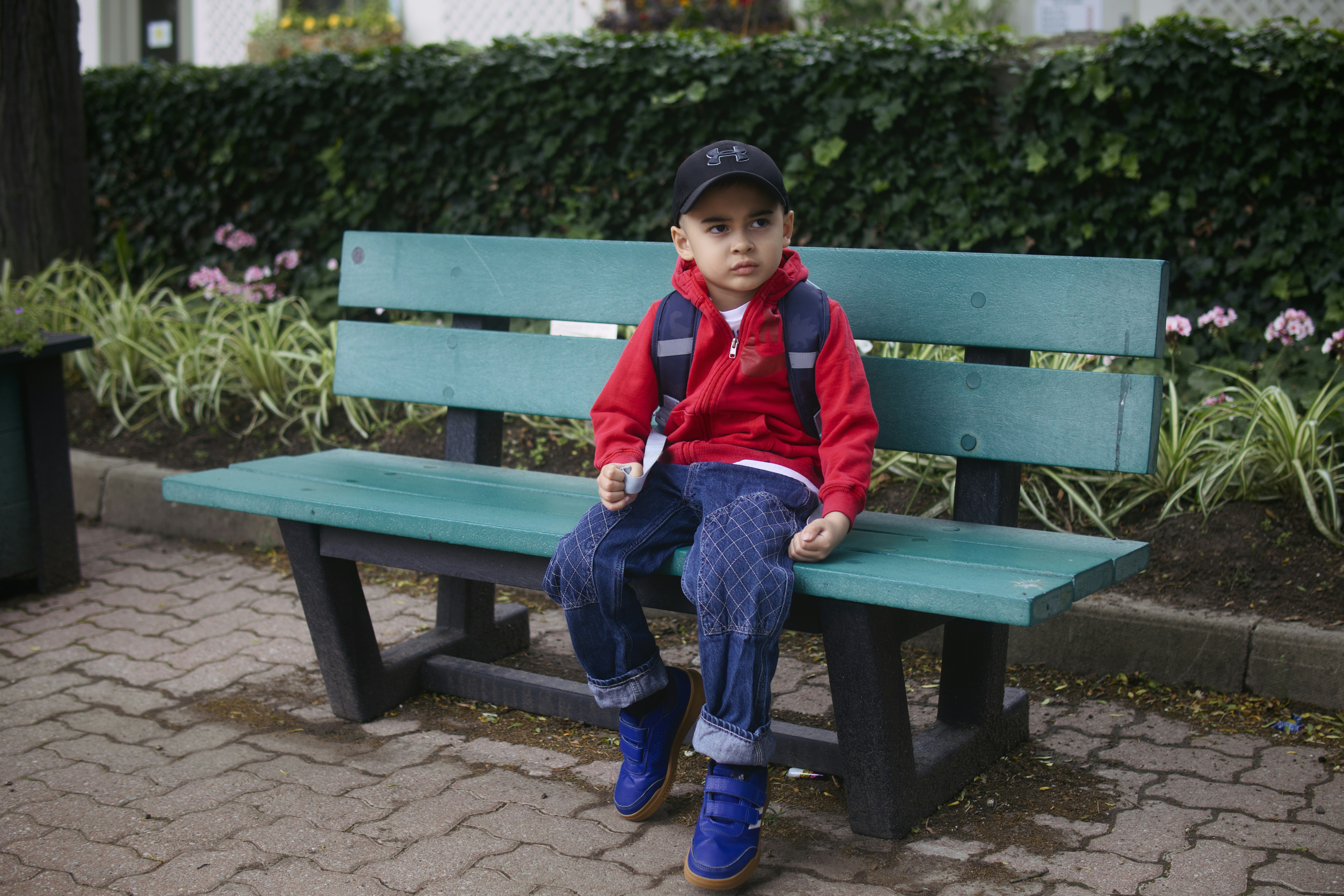 Child on a Teal Park Bench: Quiet Confidence in a Red Hoodie