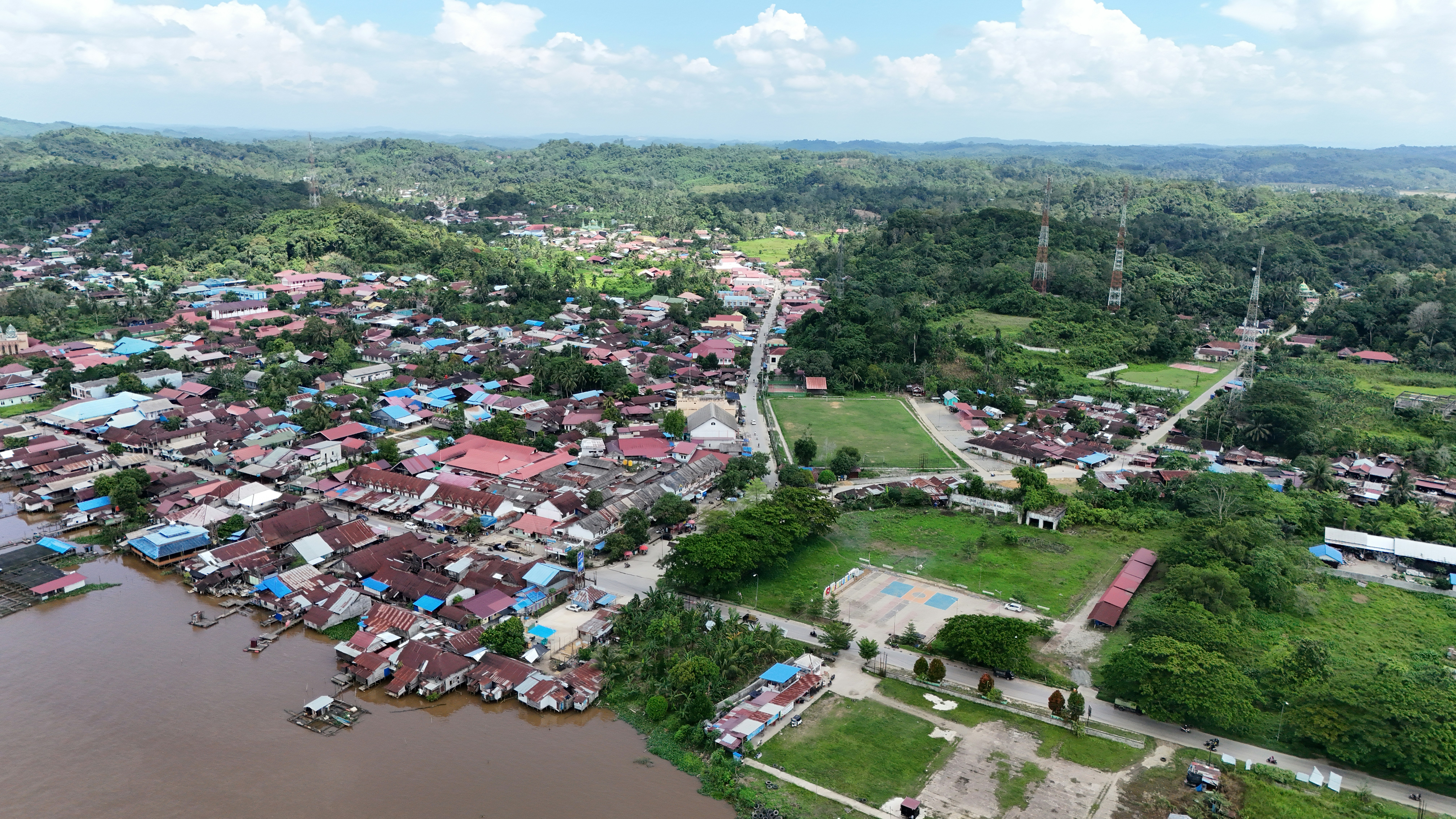 Riverbank Village from Above: Aerial Tapestry of Roofs and Red Trails