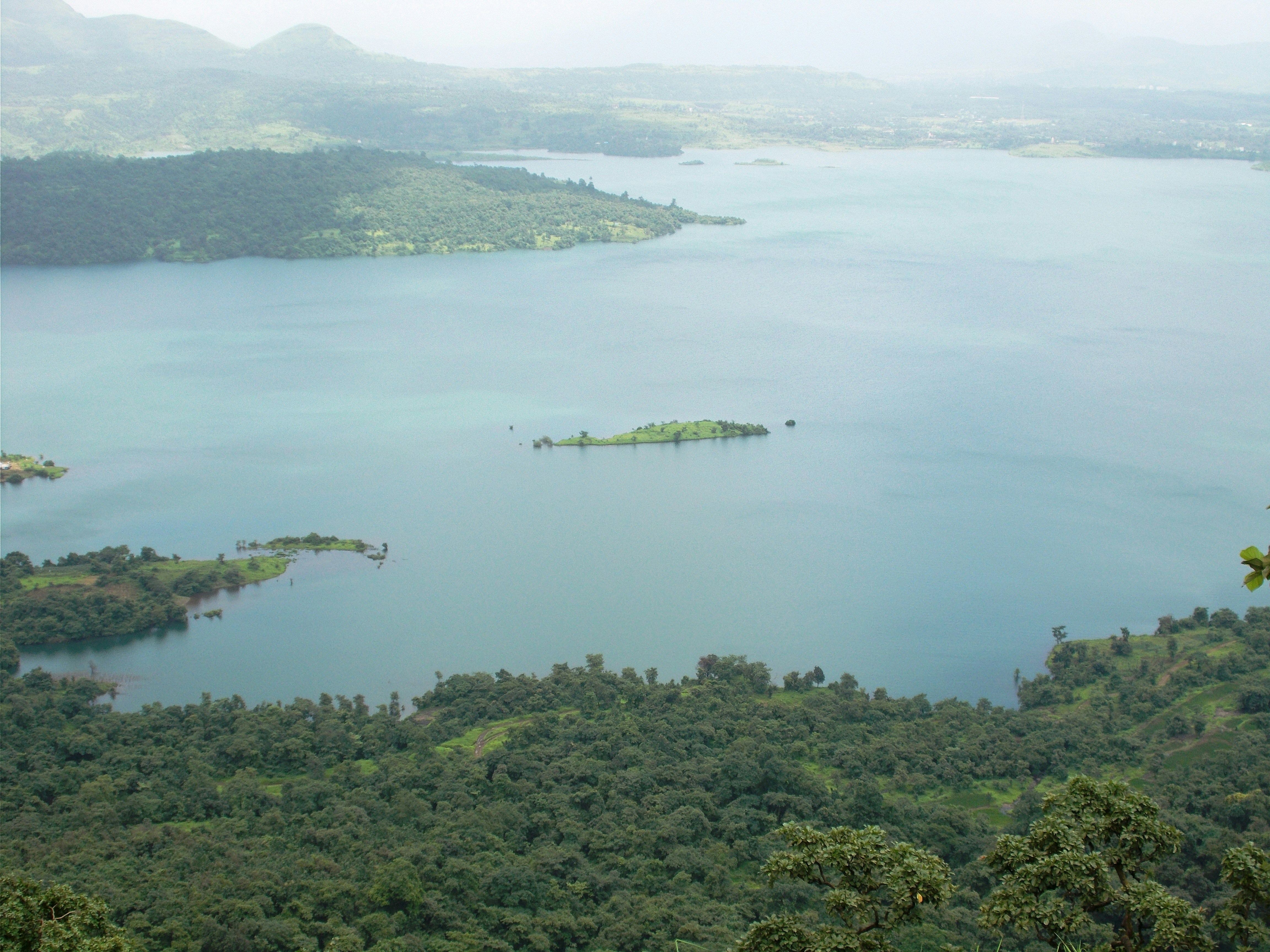 Wide lake panorama with surrounding forested shoreline and distant hills, captured from an elevated vantage point to emphasize expansive water and greenery. (Landscape photograph, natural setting.)