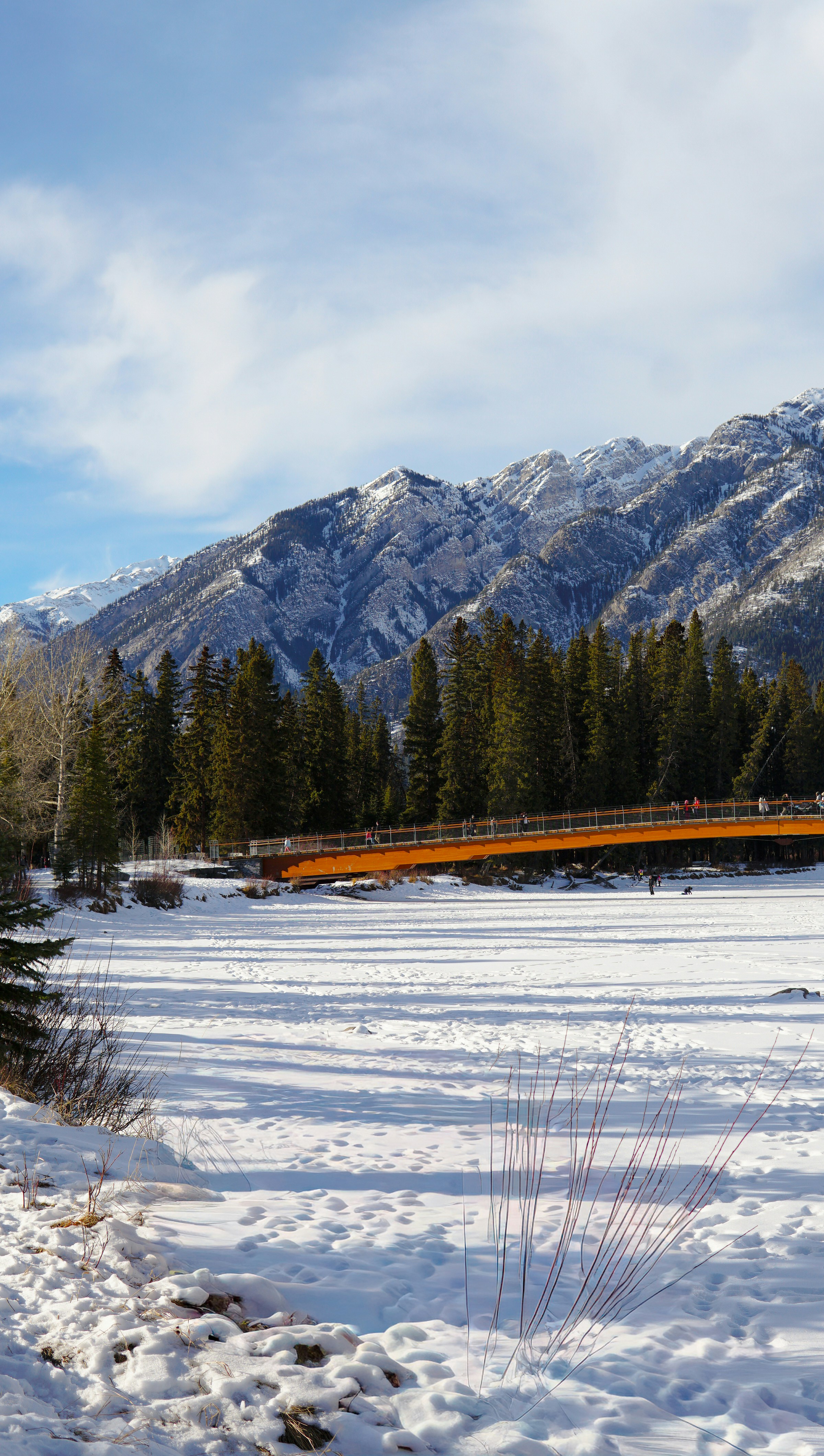 Snow-Capped Peaks and Orange Span: A Winter River Crossing