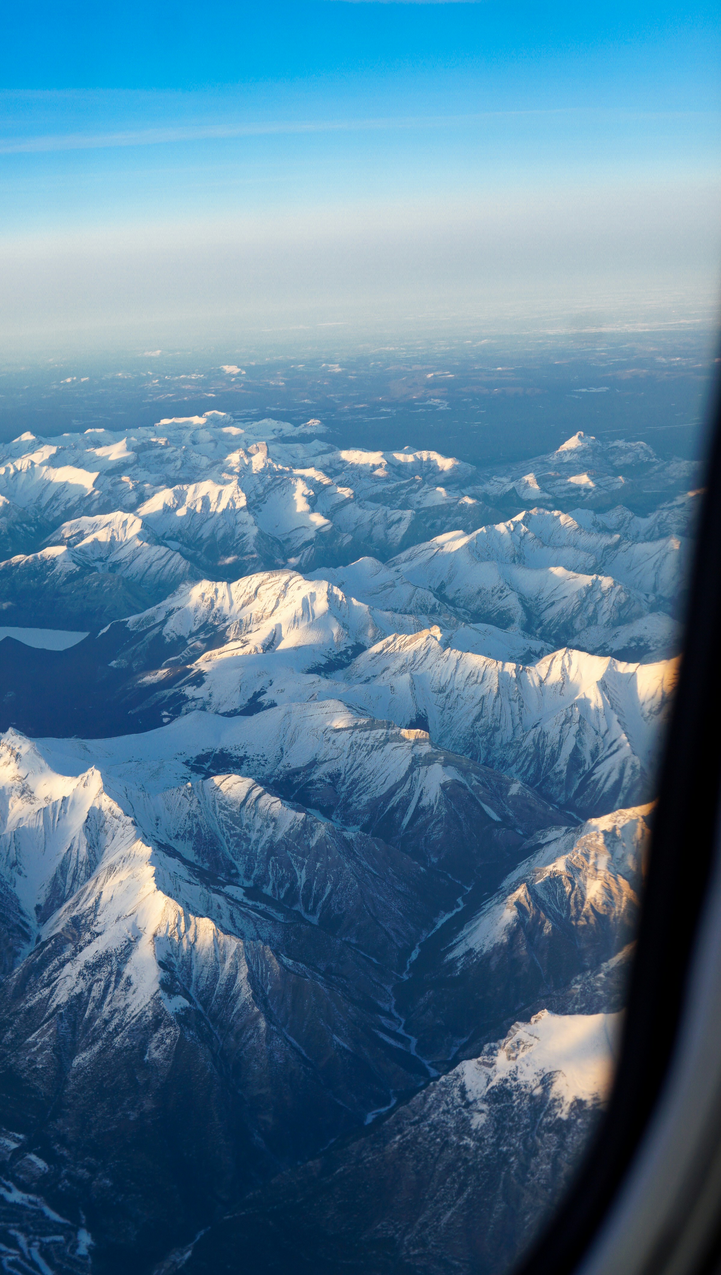 Snowy Peaks Beyond the Window: Aerial Light on Jagged Ridges