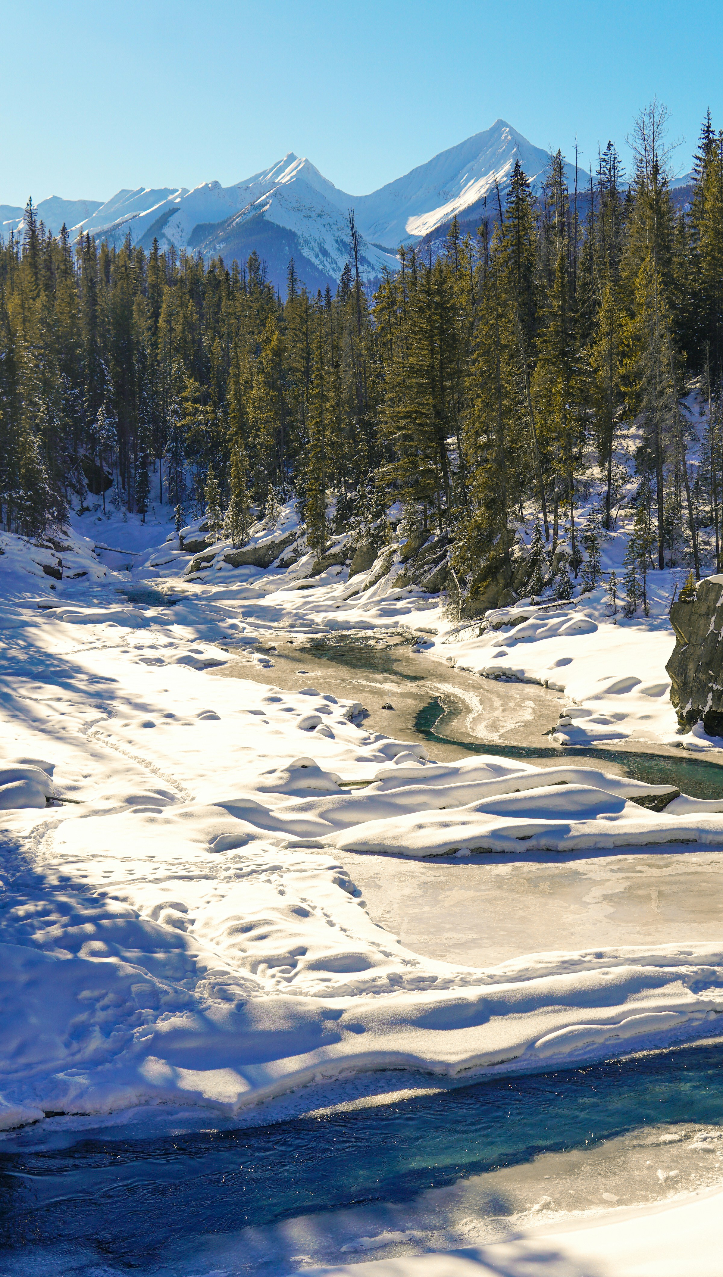 Snowbound Pines and Sapphire Stream under Alpine Peaks