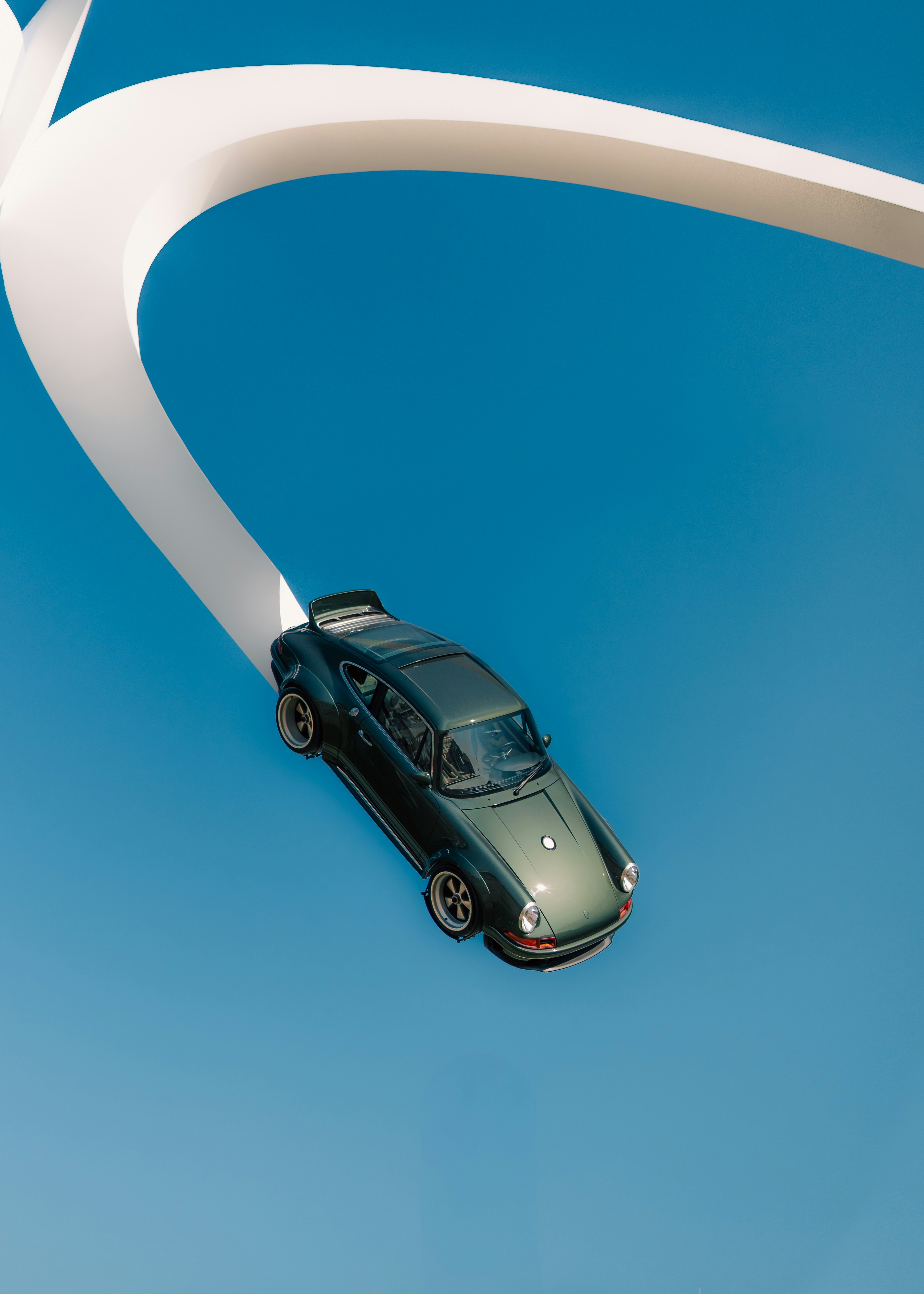 Aerial Escape: Green Classic Car Skims a Cerulean Loop