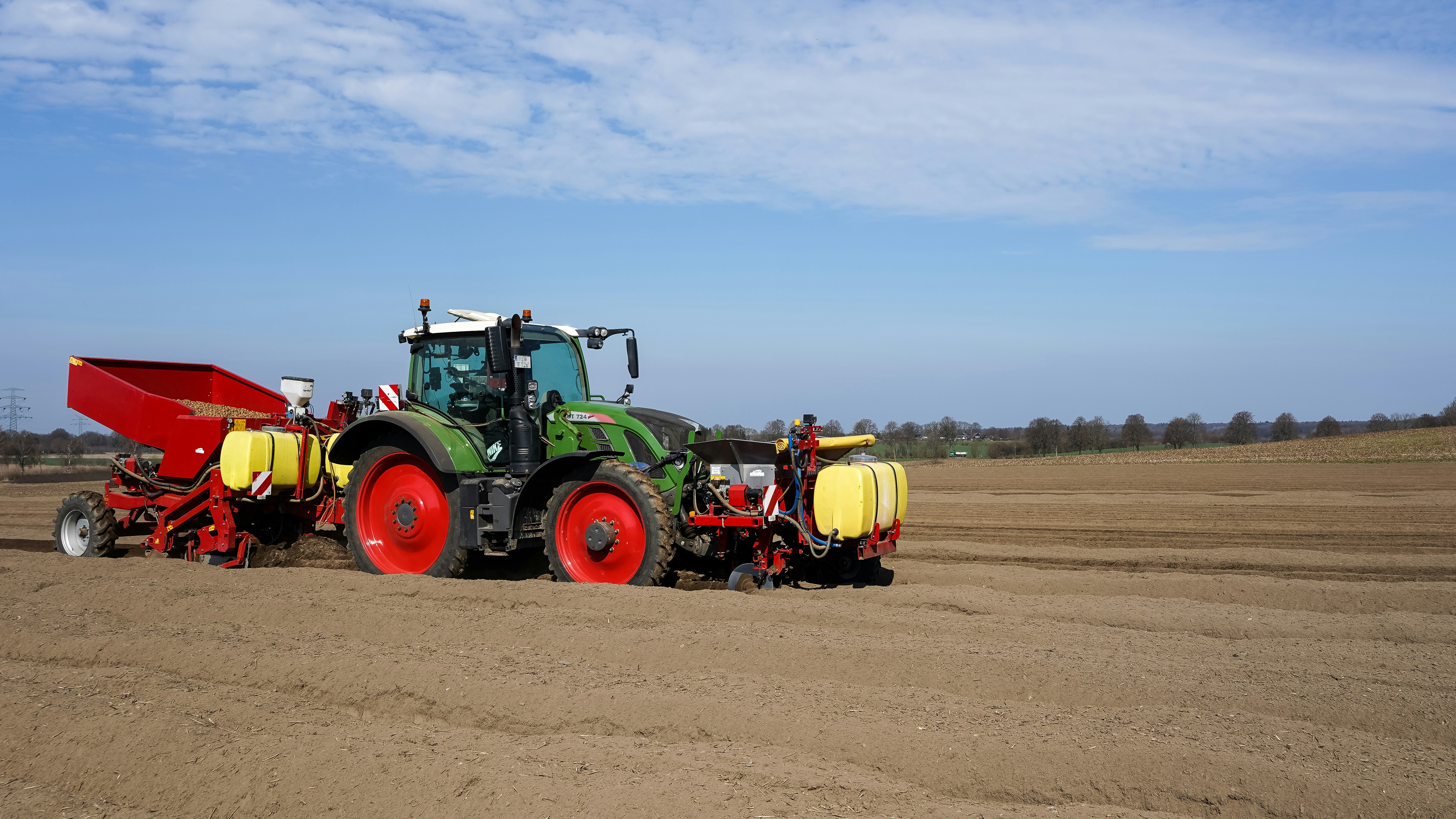 Fieldwork Duo: Green Tractor at Work in a Row of Freshly Billed Soil