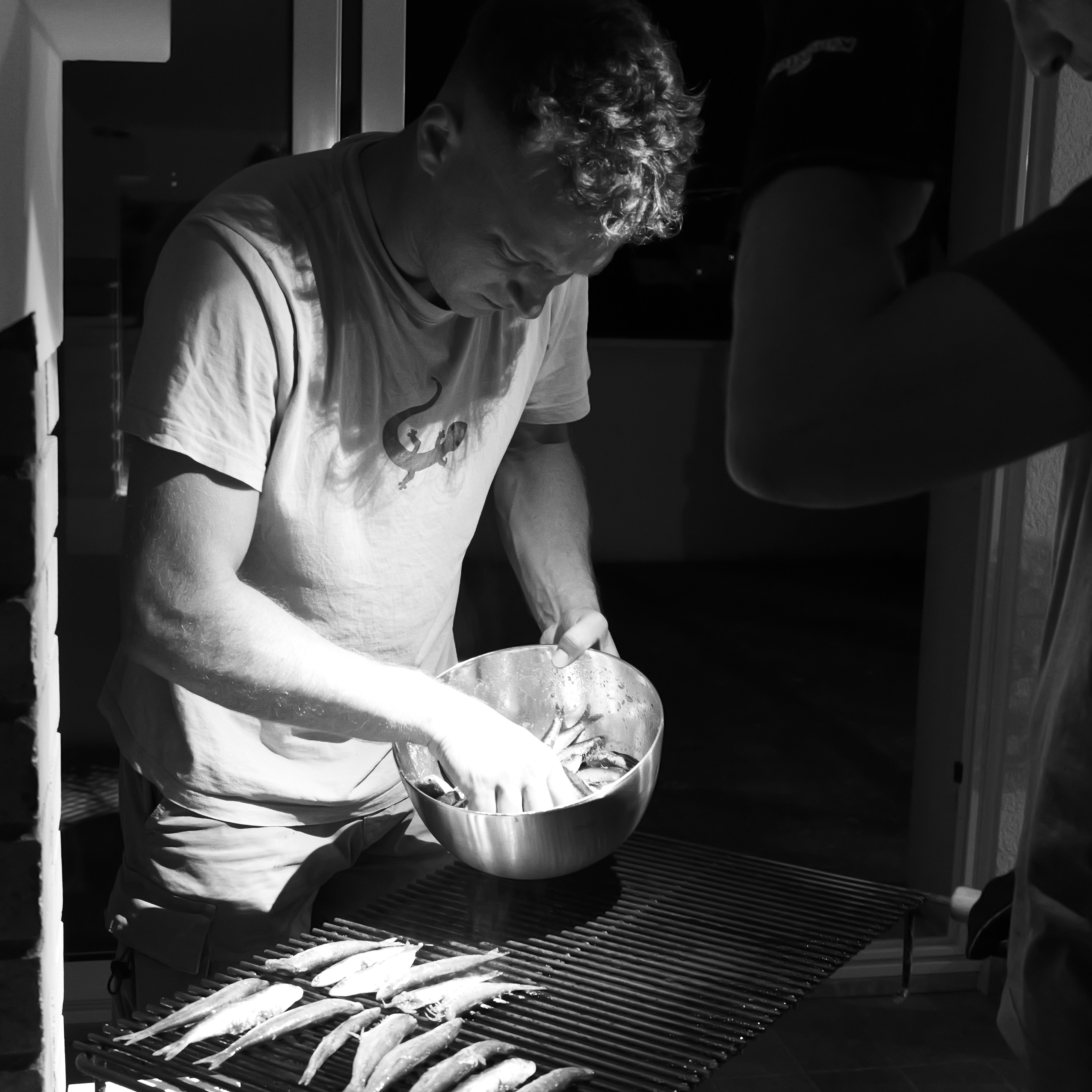 Hands at the Grill: A Quiet Moment of Grilled Fish and Bowl