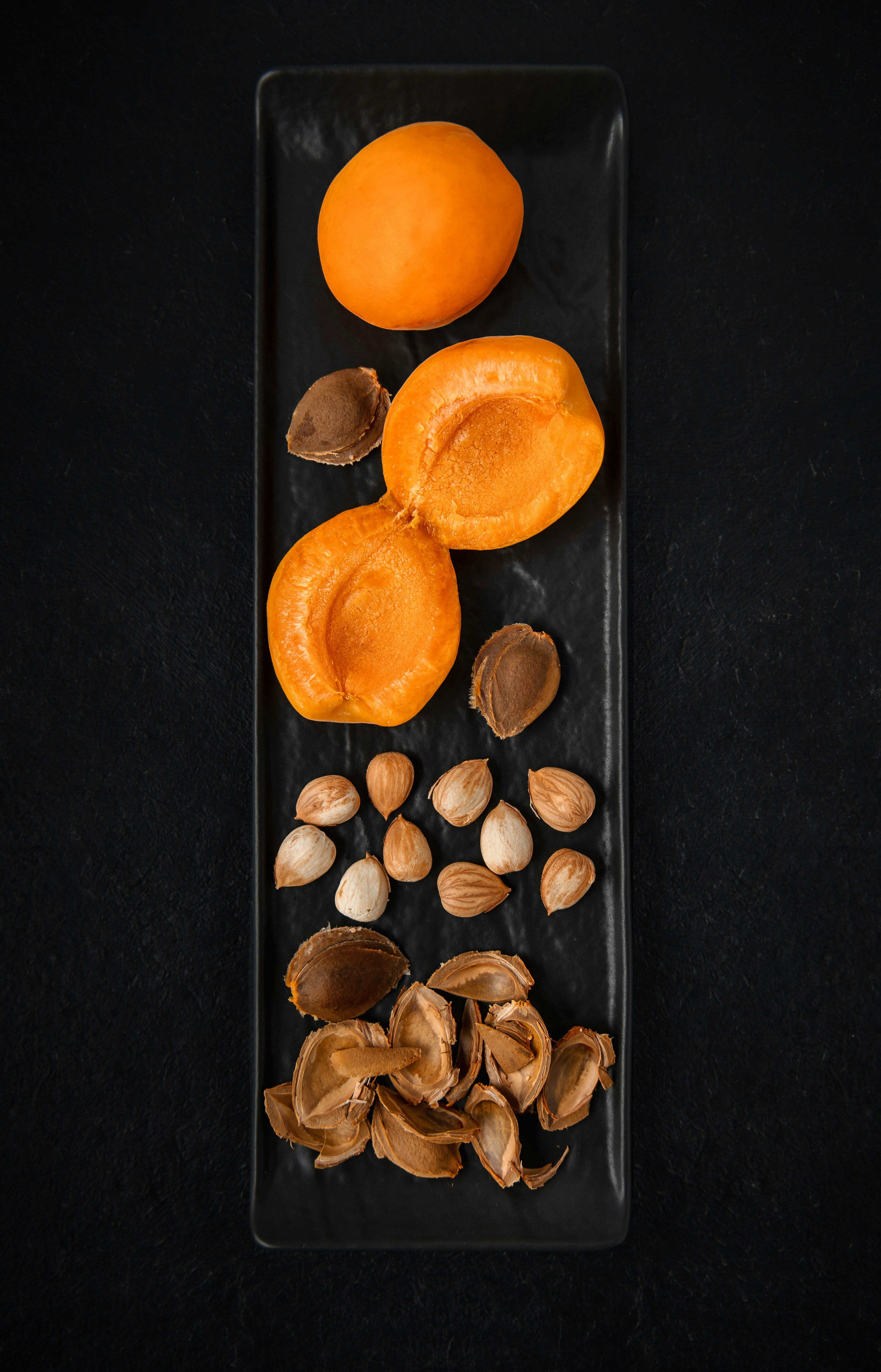 Vertical tray of dried apricots and nuts on a black backdrop