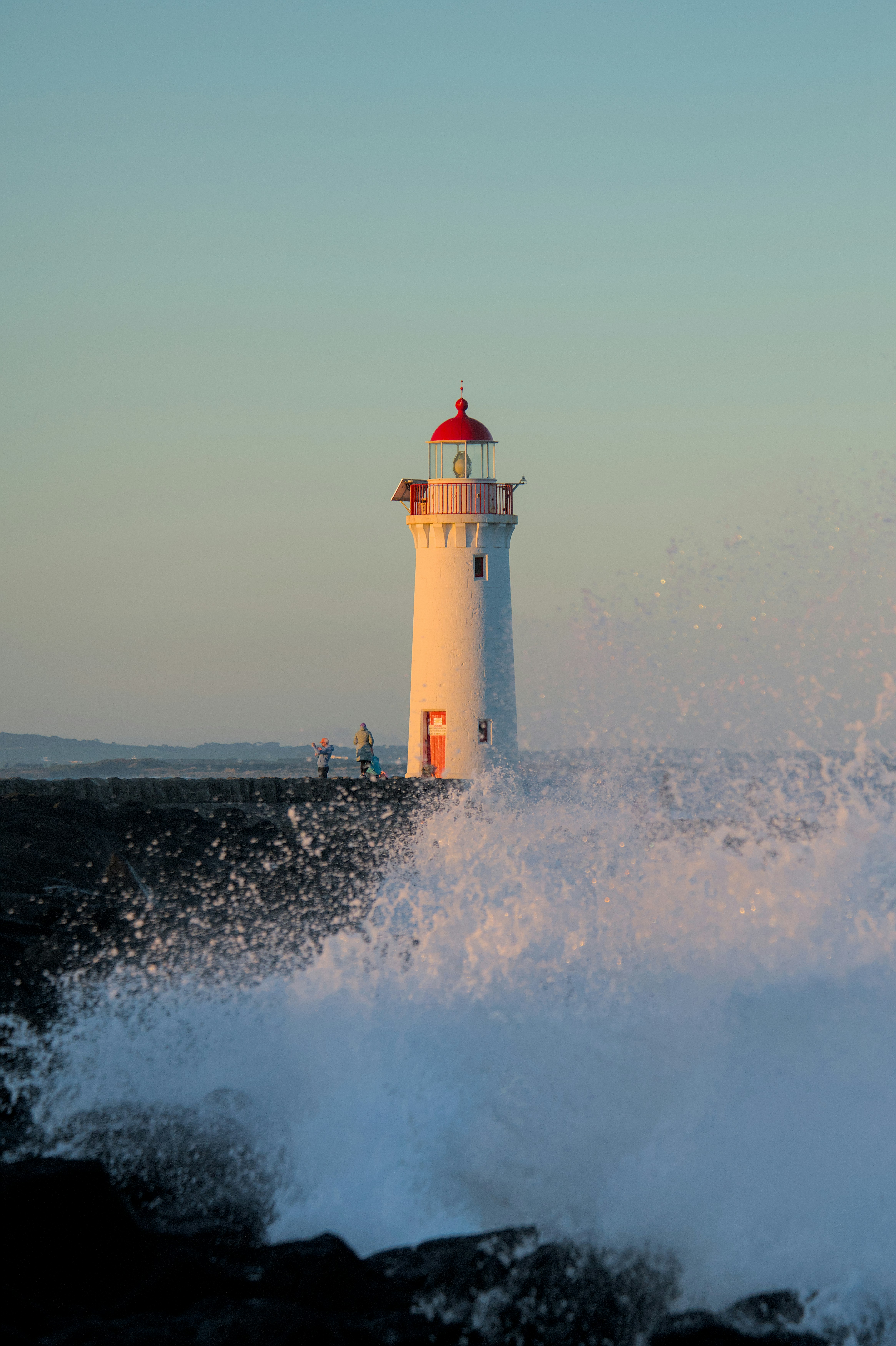 Beacon at the Edge: Waves Clash with a Quiet Lighthouse
