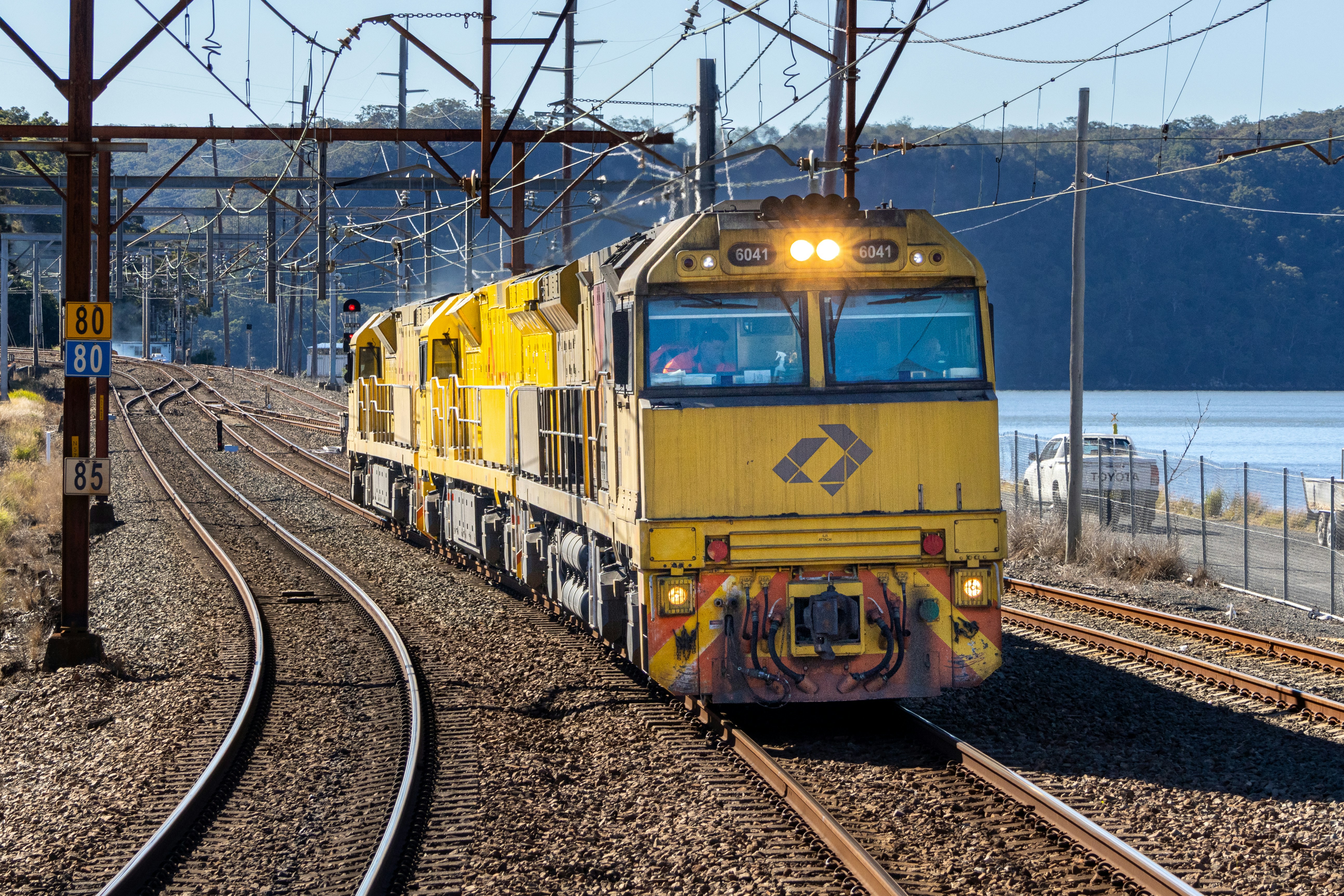 Yellow Locomotive Rounds the Curve Along a Coastal Rail Corridor
