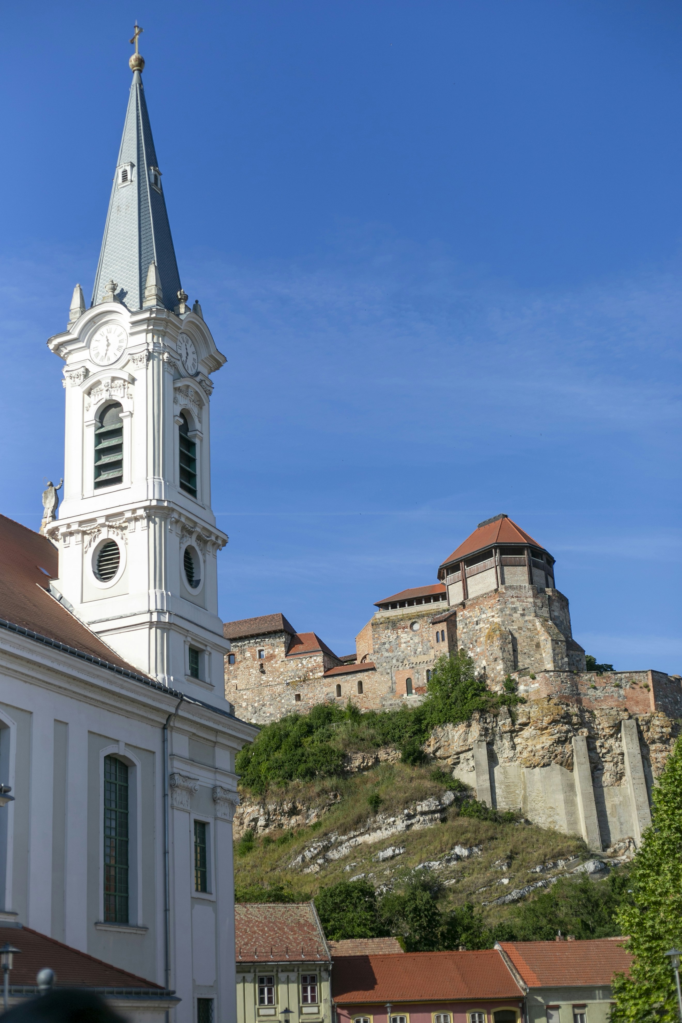 White Church Tower Against a Blue Sky Over a Fortress Hill