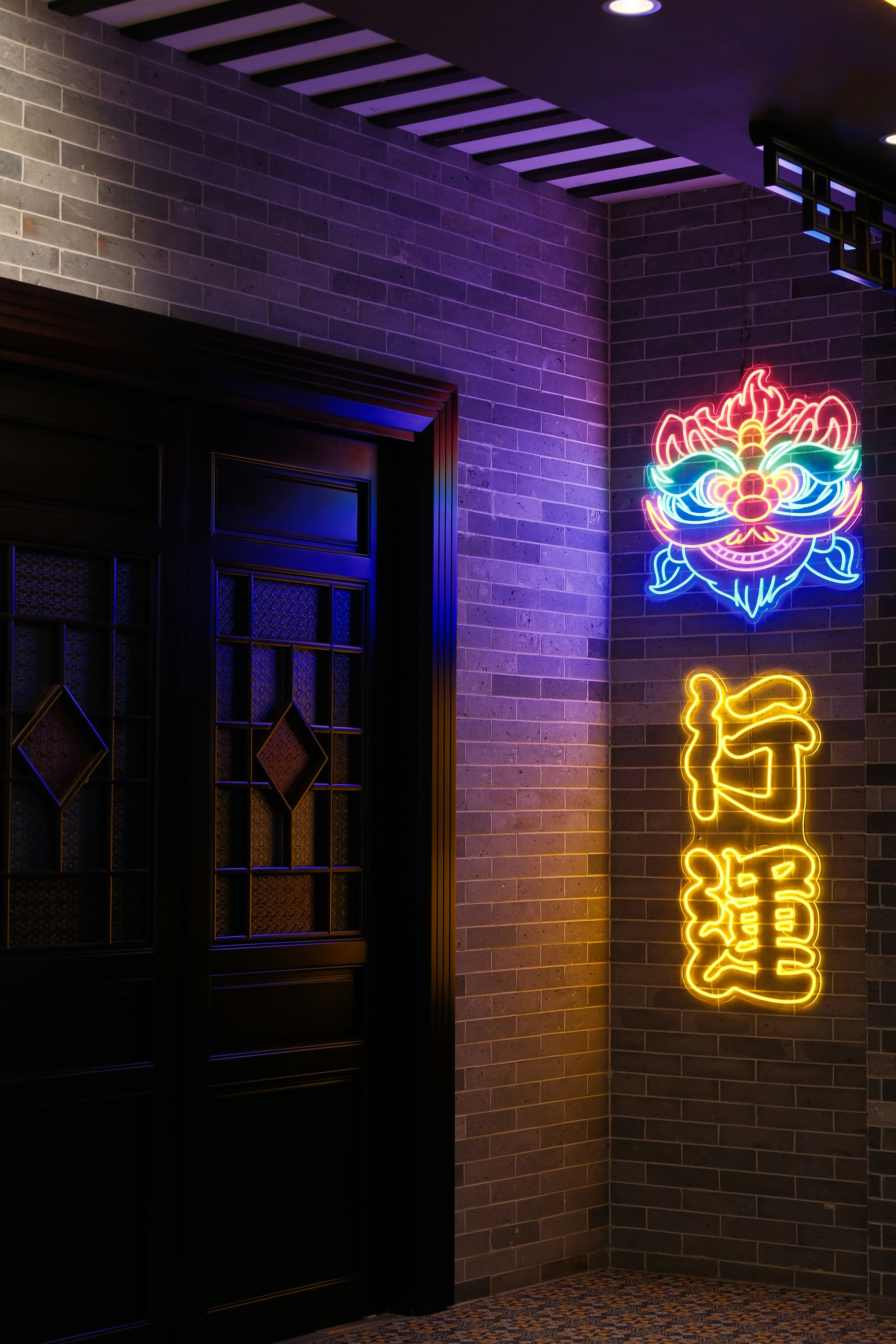 Neon dragon sign and Chinese characters glow along a brick wall beside a dark wooden doorway in a moody, urban interior.