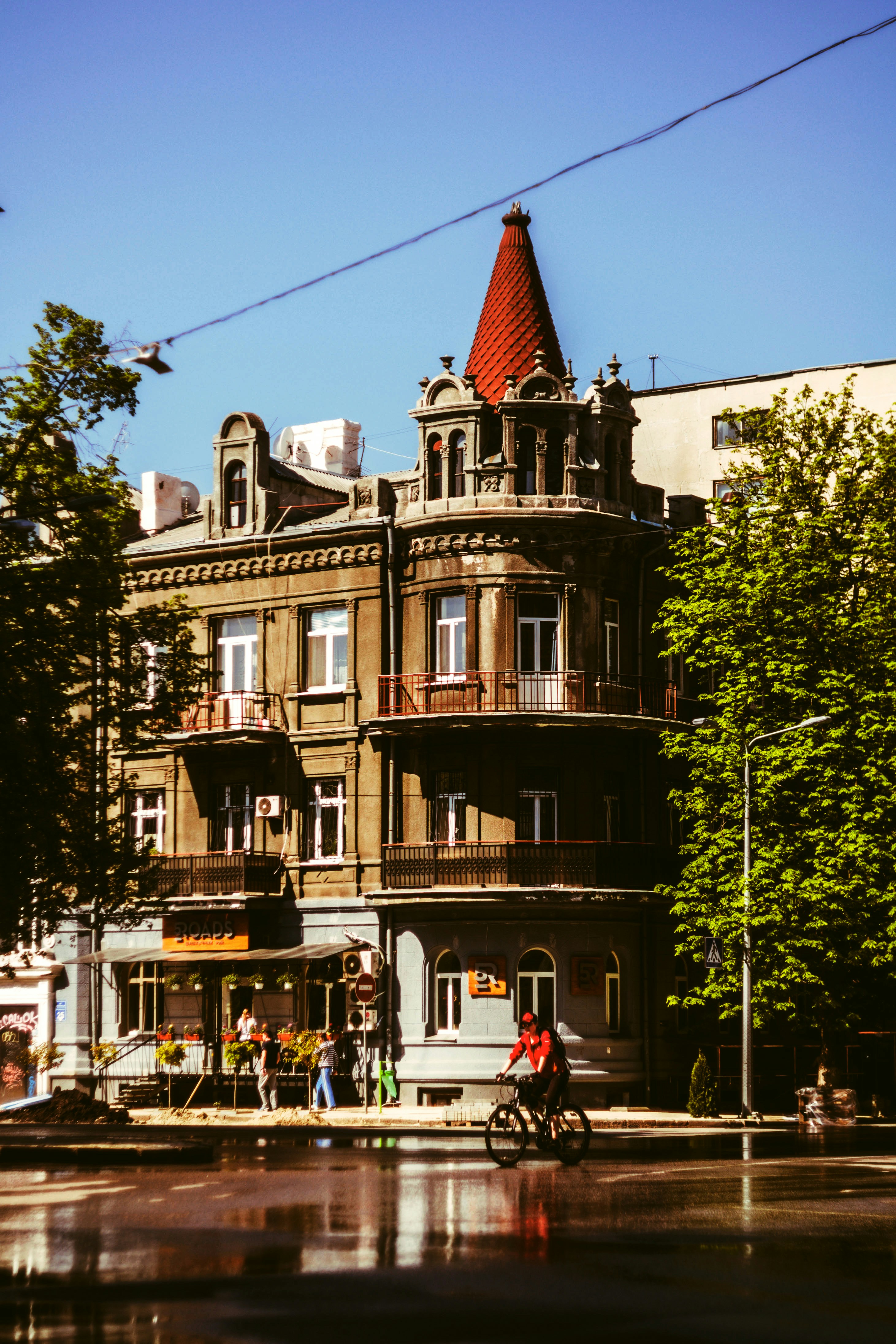 Corner turreted facade with a cyclist on a sunlit city street