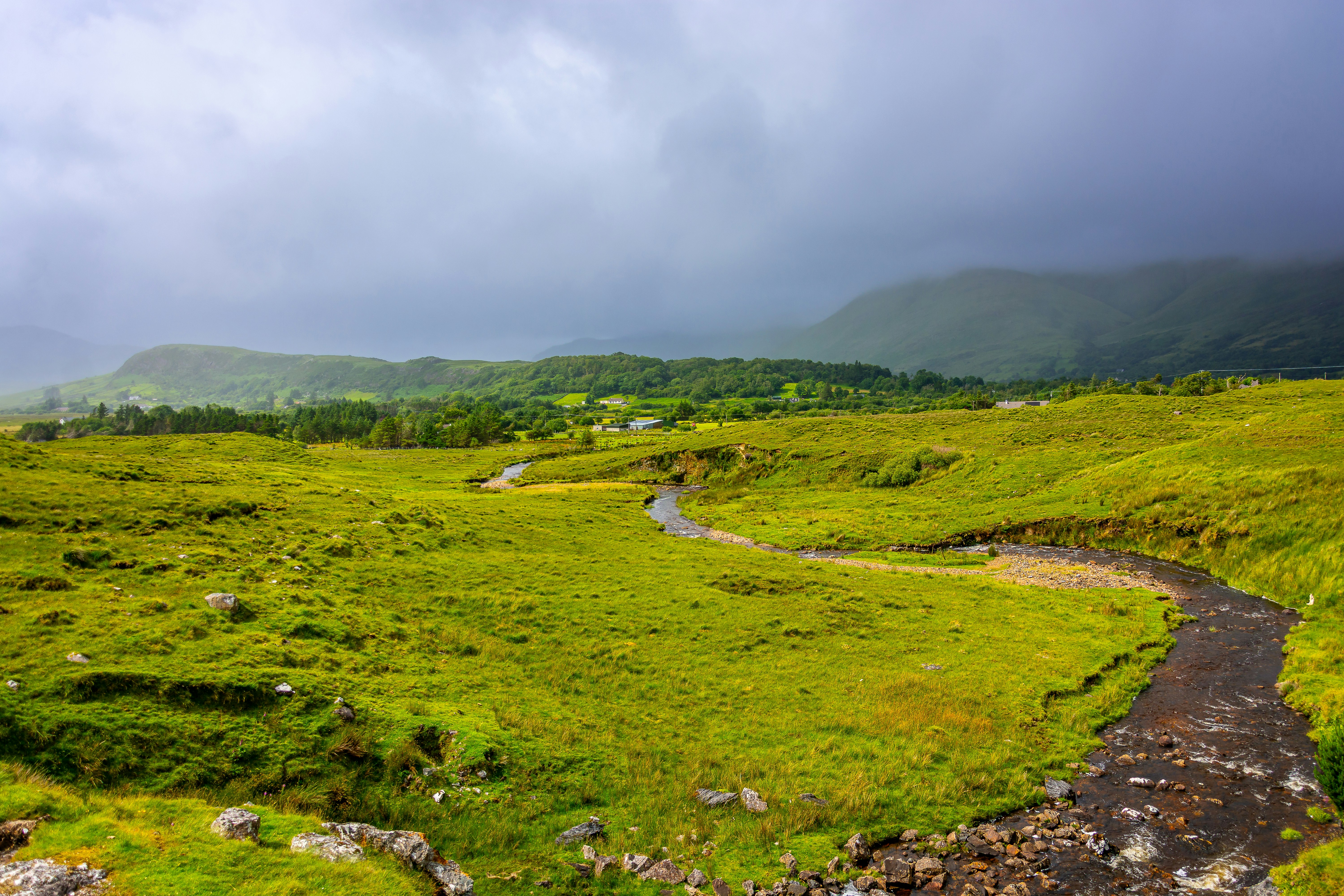 Meandering Path through Emerald Moor Under a Stormy Crown