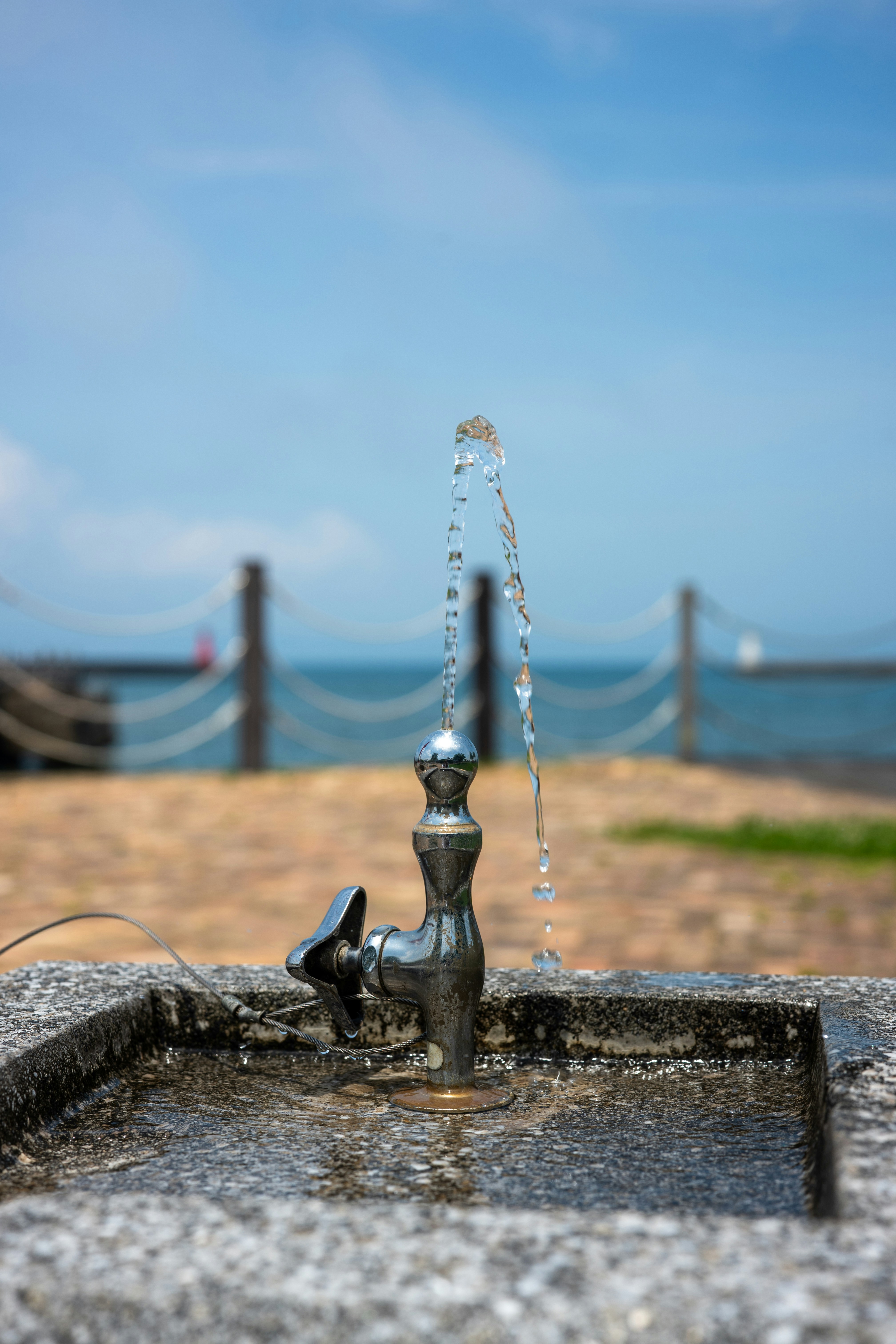 Towering water arc: a sunlit fountain at the seaside