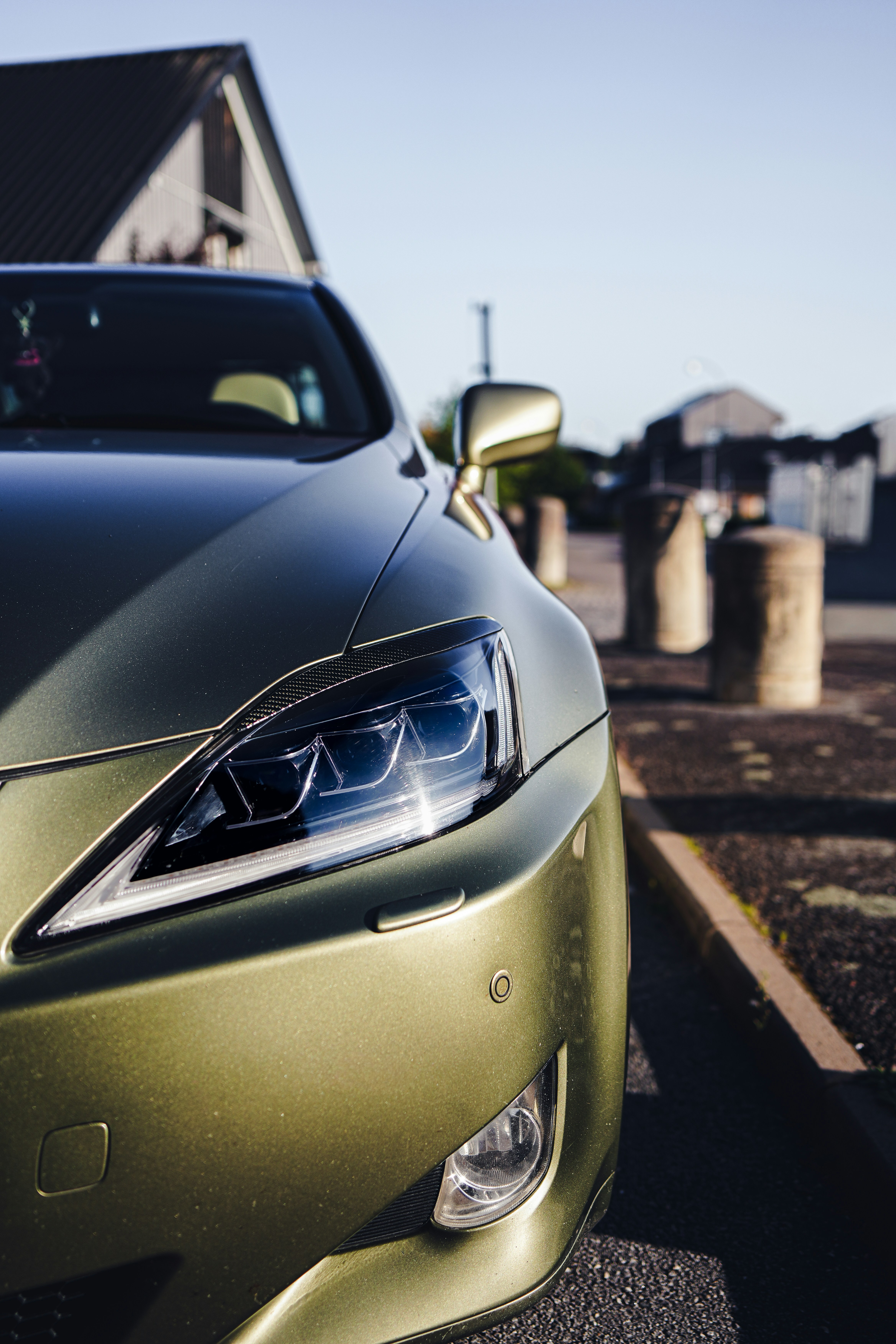 Olive-green front-quarter of a sleek sedan glinting in morning light