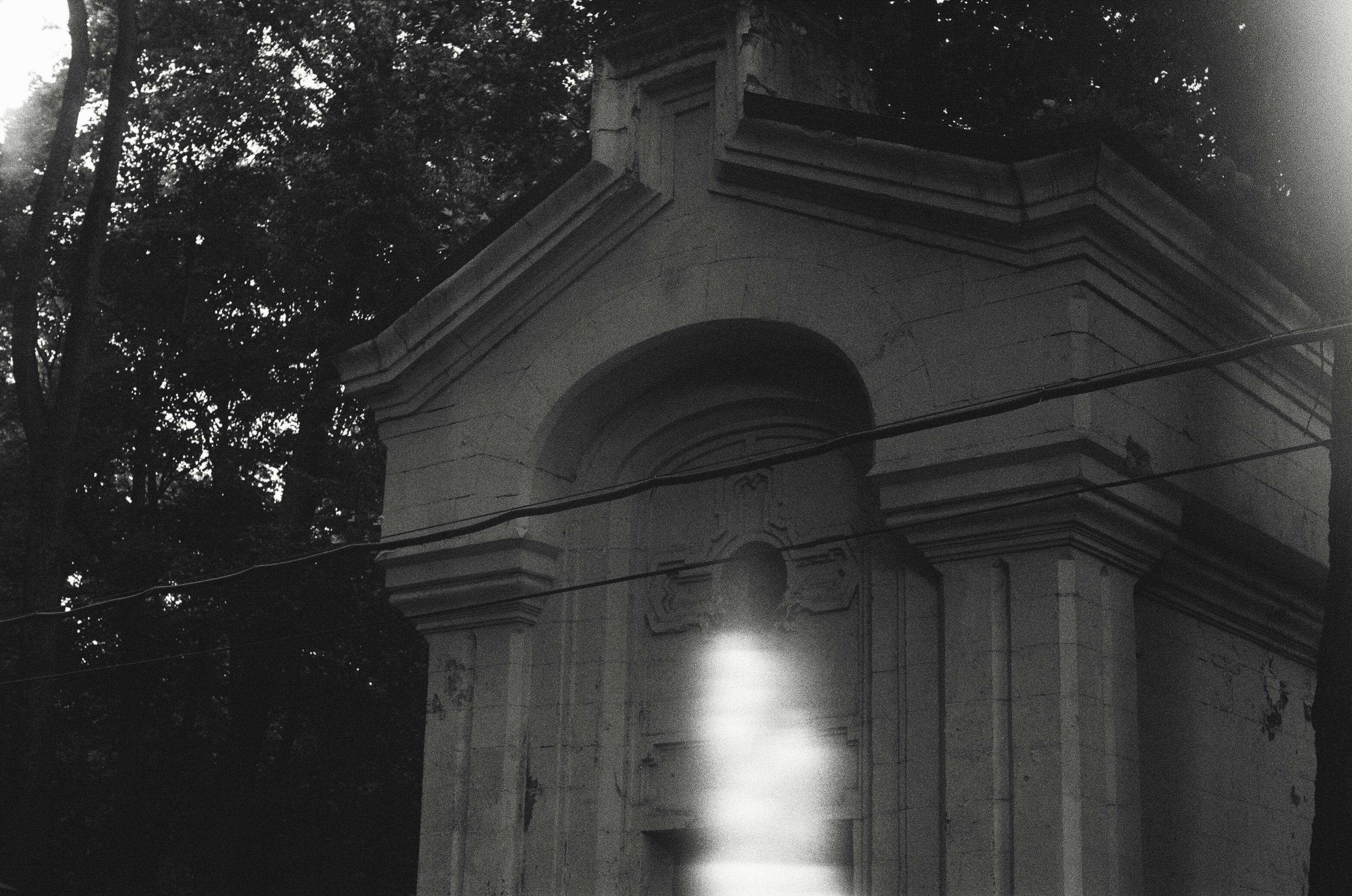 Ghostly Arch: A Moment Inside a Shaded Cemetery Gate