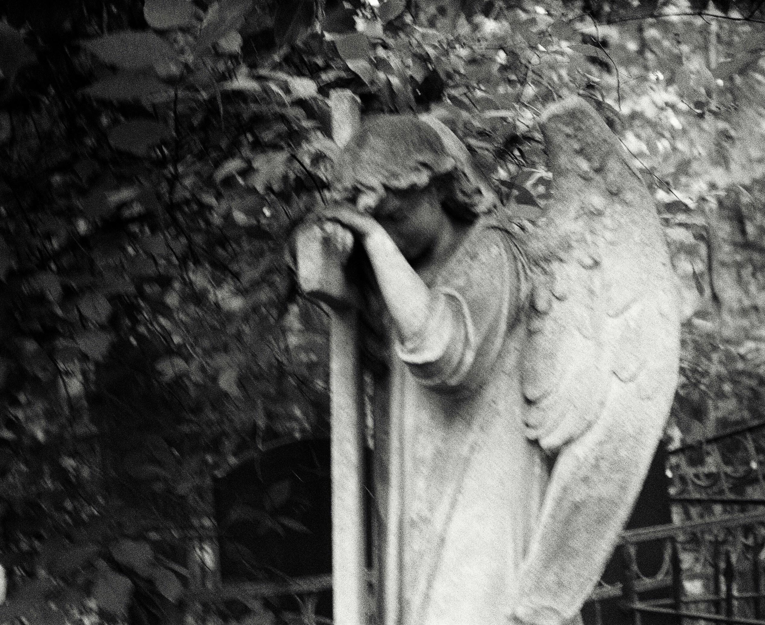 A granite angel statue standing over an old grave at Vvedenskoye Cemetery in Moscow. The sculpture embodies eternal peace and silent memorial art, surrounded by the historic atmosphere of one of the city's oldest necropolises.
