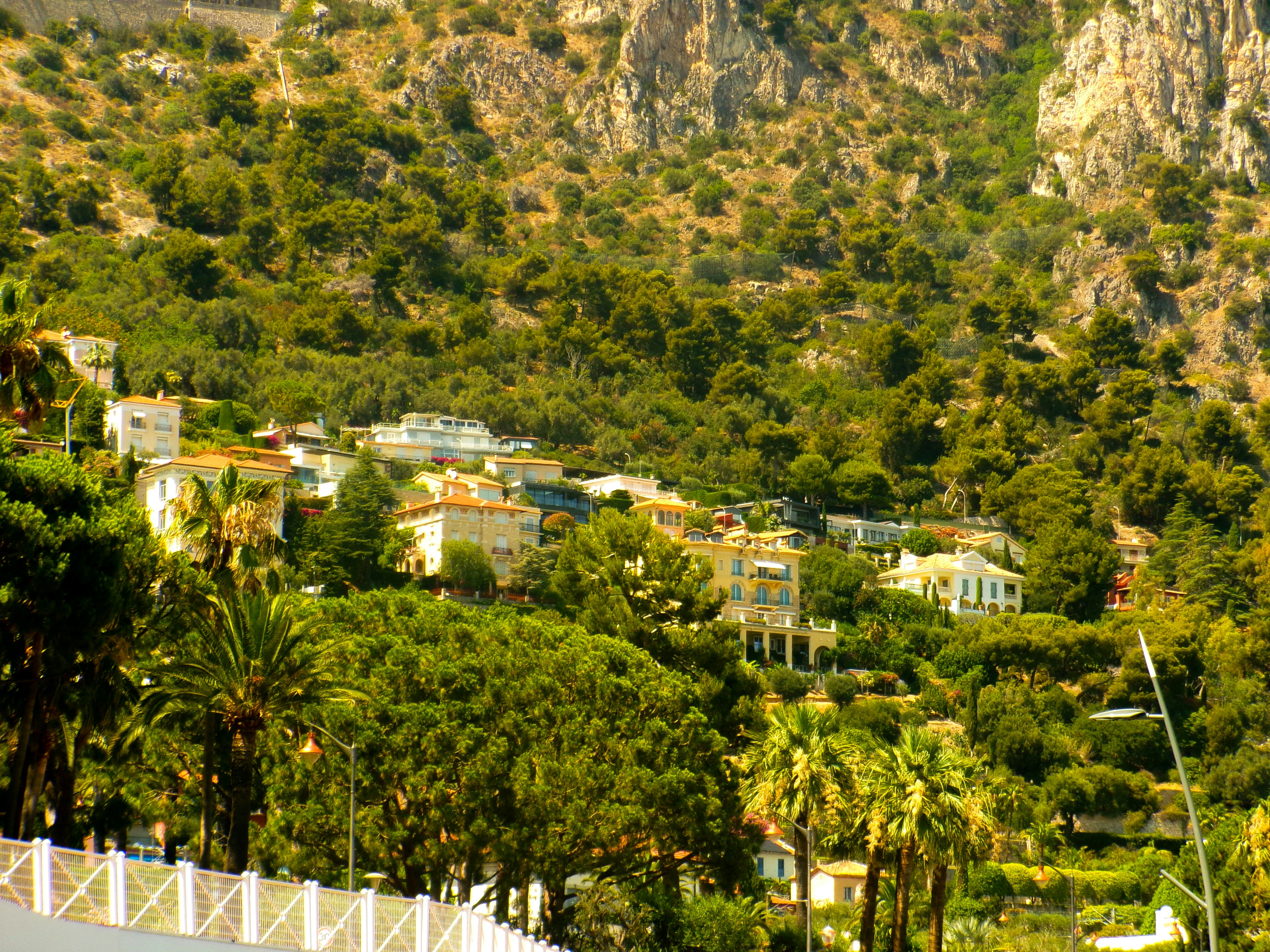 Sunlit hillside village tucked beneath rugged cliffs