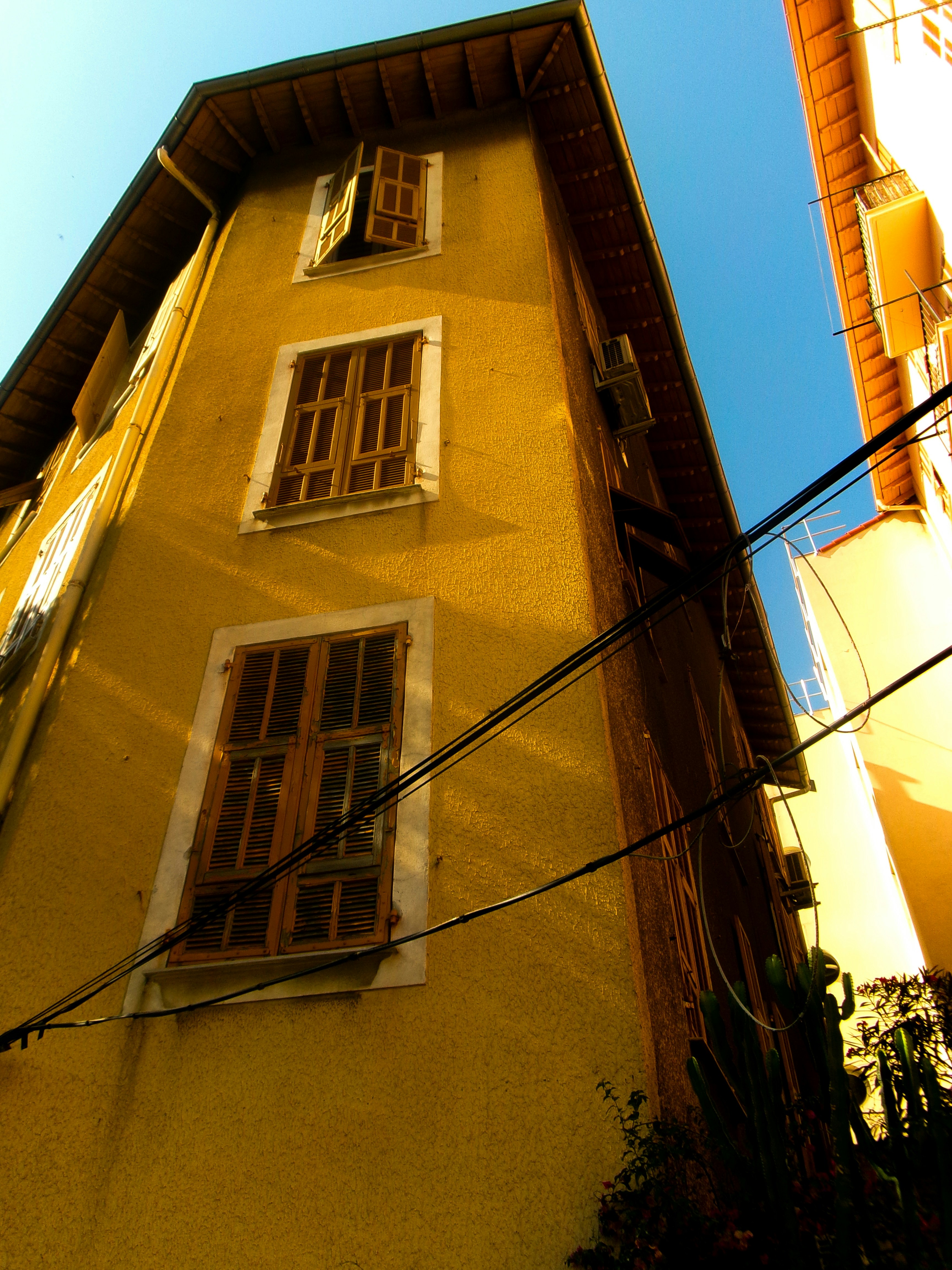 Sunlit Yellow Facade: A Building Reaches Toward a Bright Sky