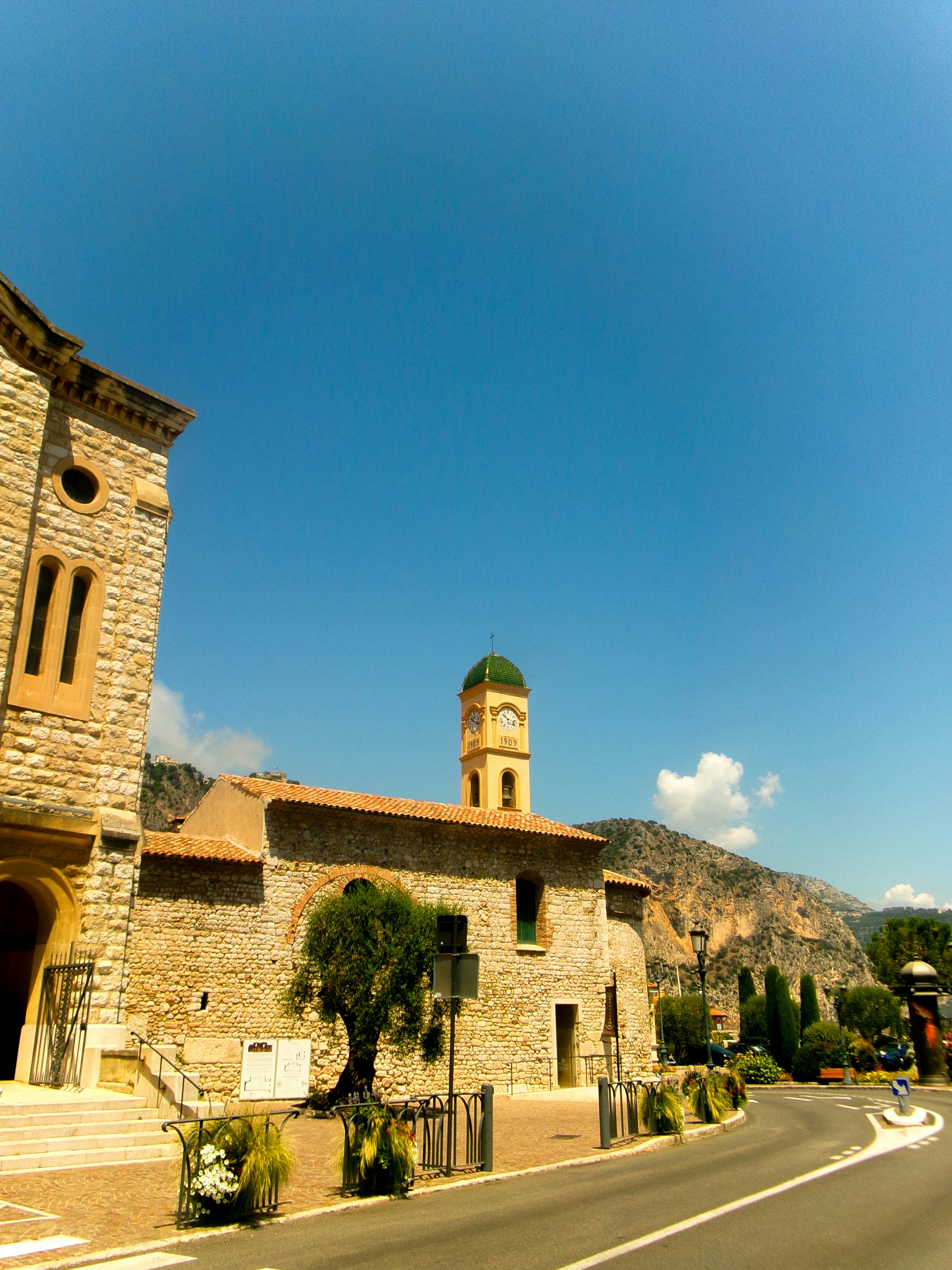 Sunlit village clock tower rising above stone houses