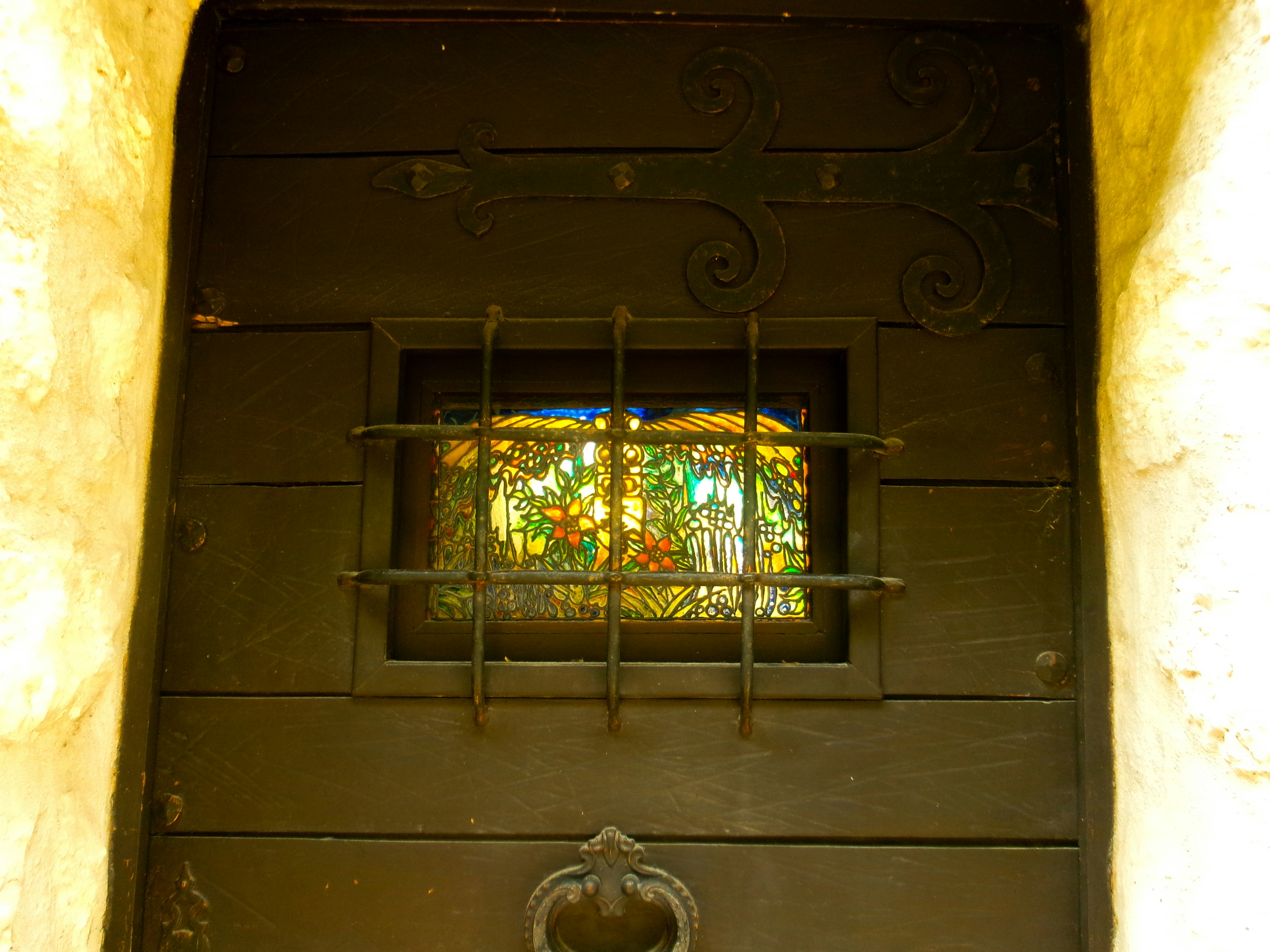 Stained Window Gated by Iron Bars in a Rustic Doorway