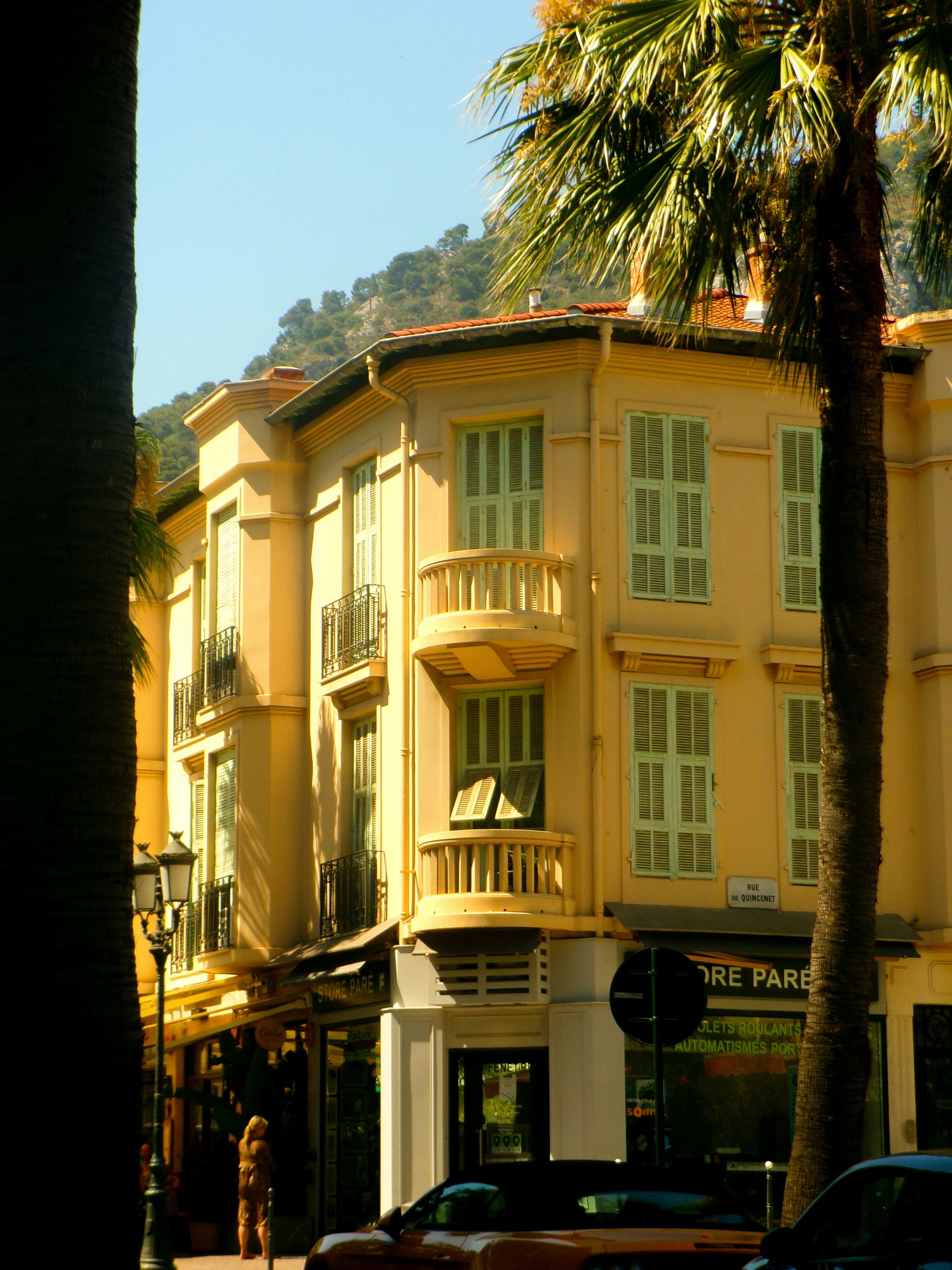 Sunlit yellow Victorian on a palm-lined street