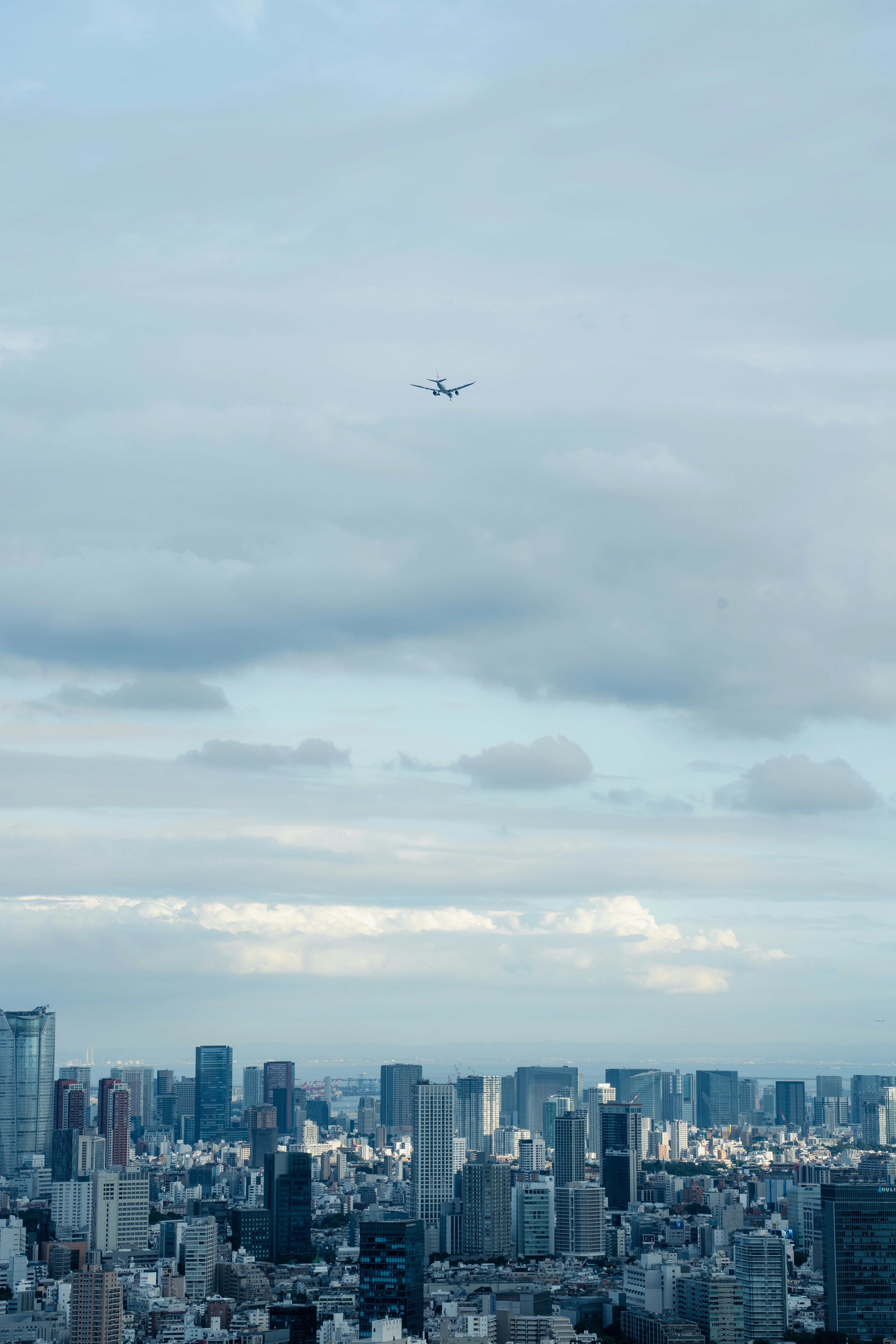 City in the Sky: Aircraft Silhouette Above the Urban Wake