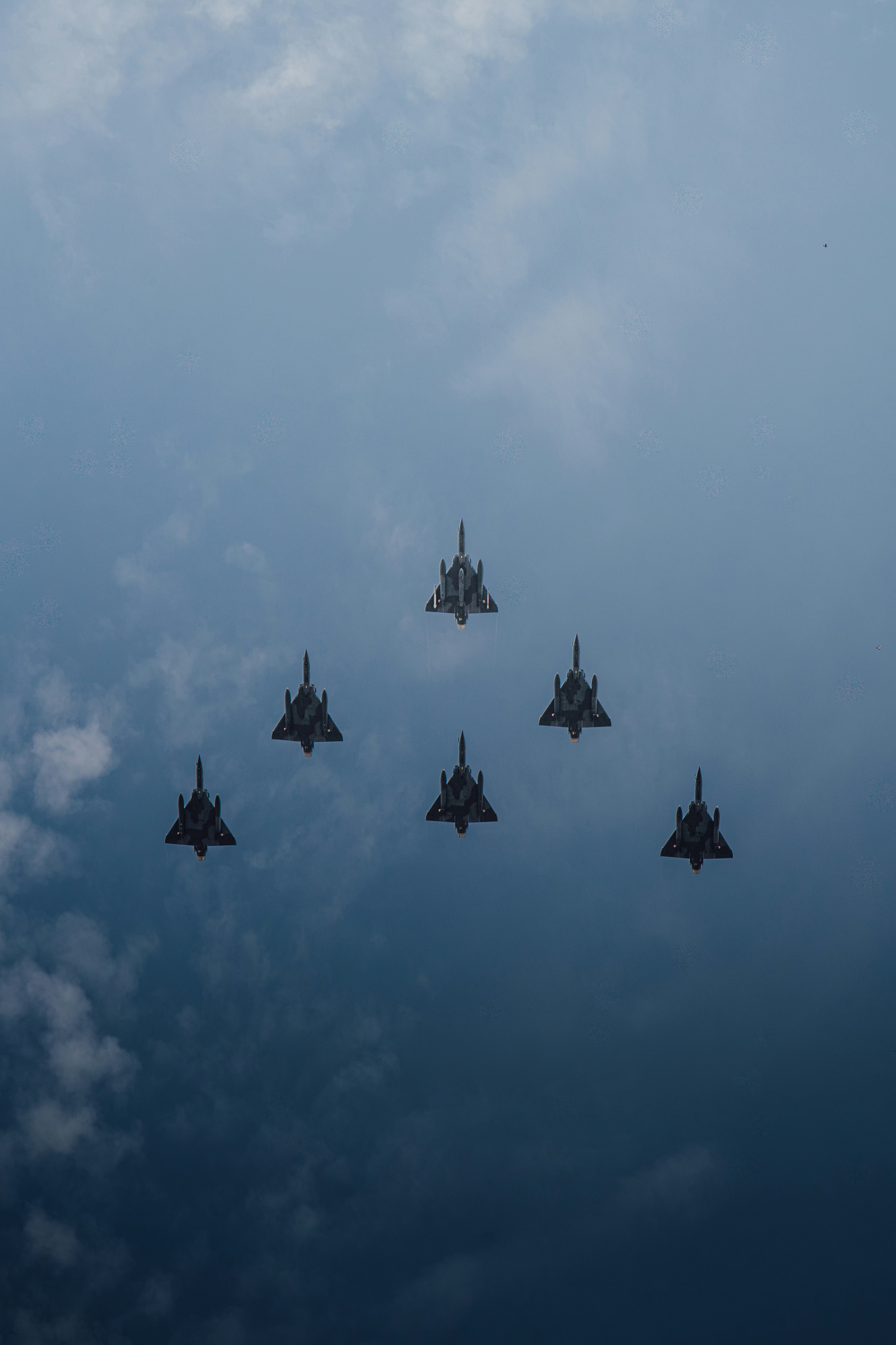 V-formation of X-73 jets piercing a blue sky