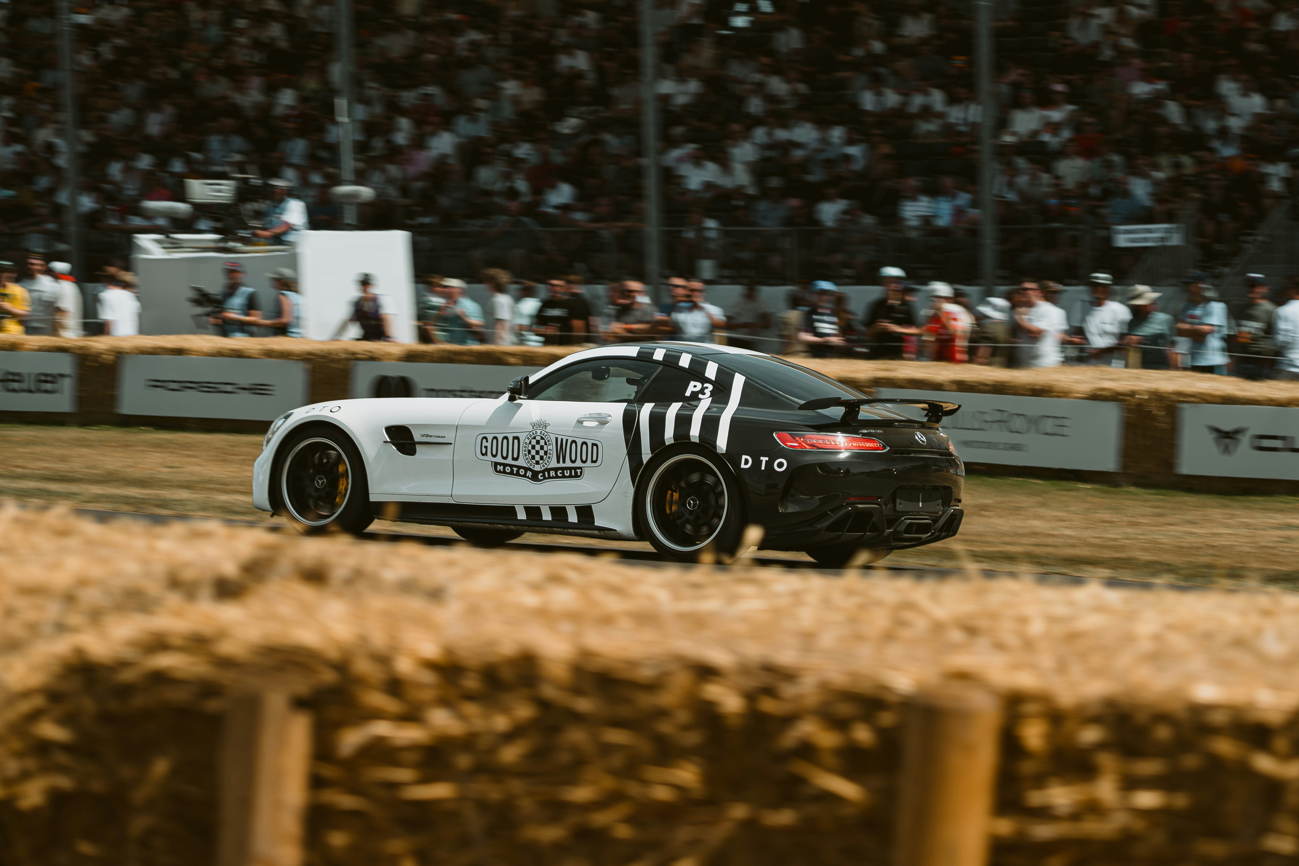 Sports car with unique livery racing on a dirt track.
