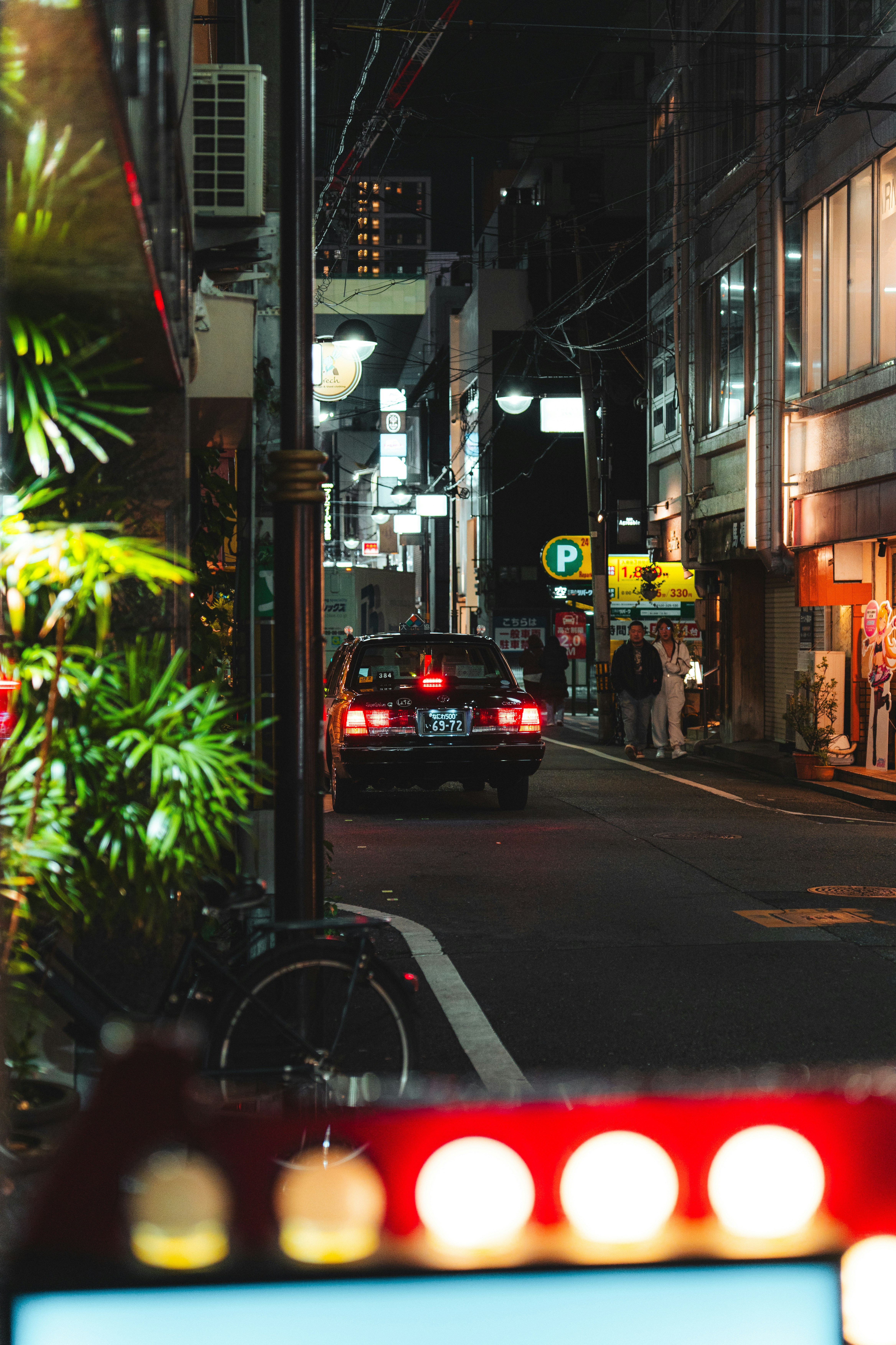 Neon Street Pulse: Nighttime Car Pauses Under Urban Glow