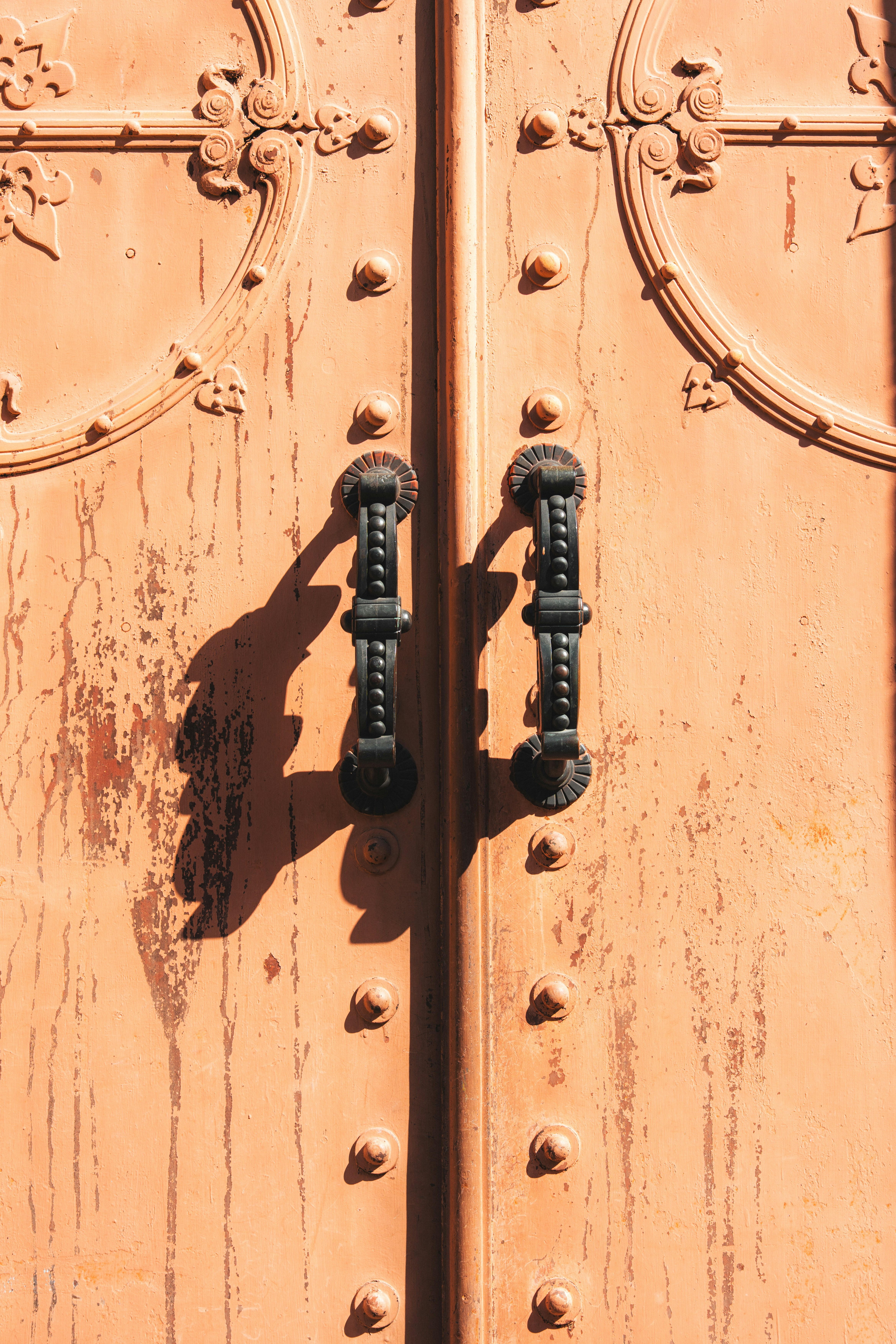 Iron Veins in Sunset Orange: Dual Door Handles on Aged Panels