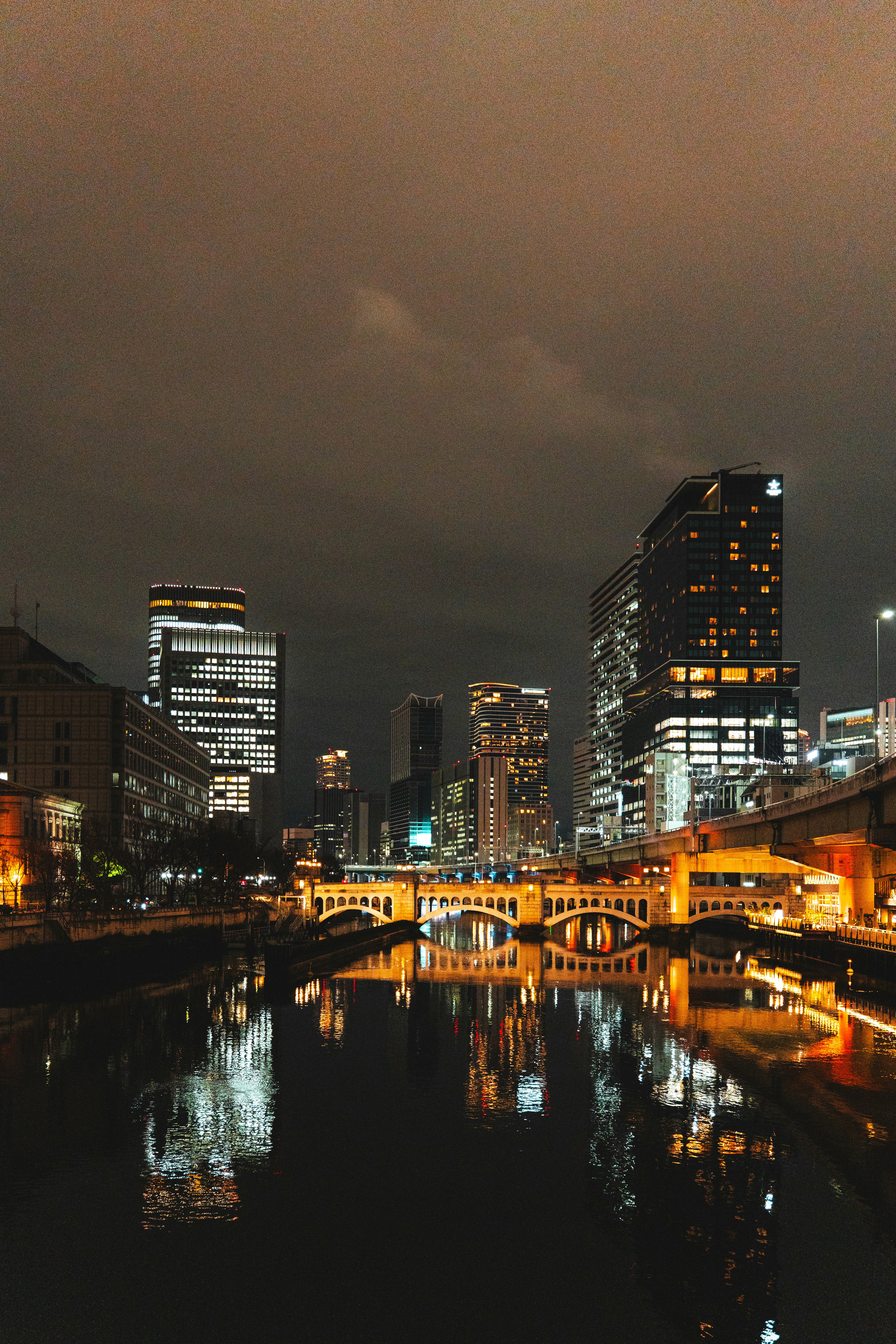 City by the River at Dusk: Neon Reflections and Arched Bridges