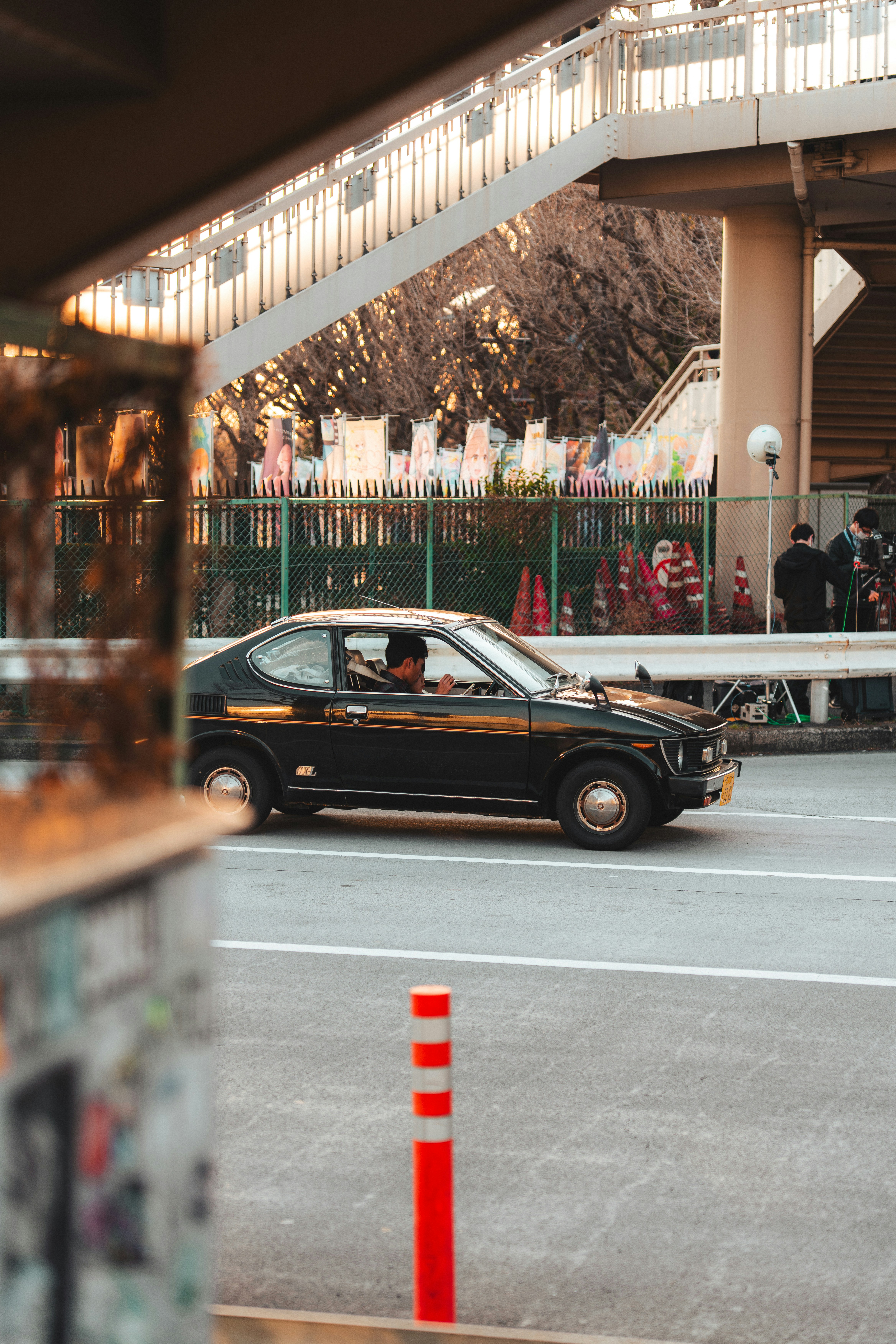 Midday Ride: A Classic Black Sedan on a Busy Urban Street