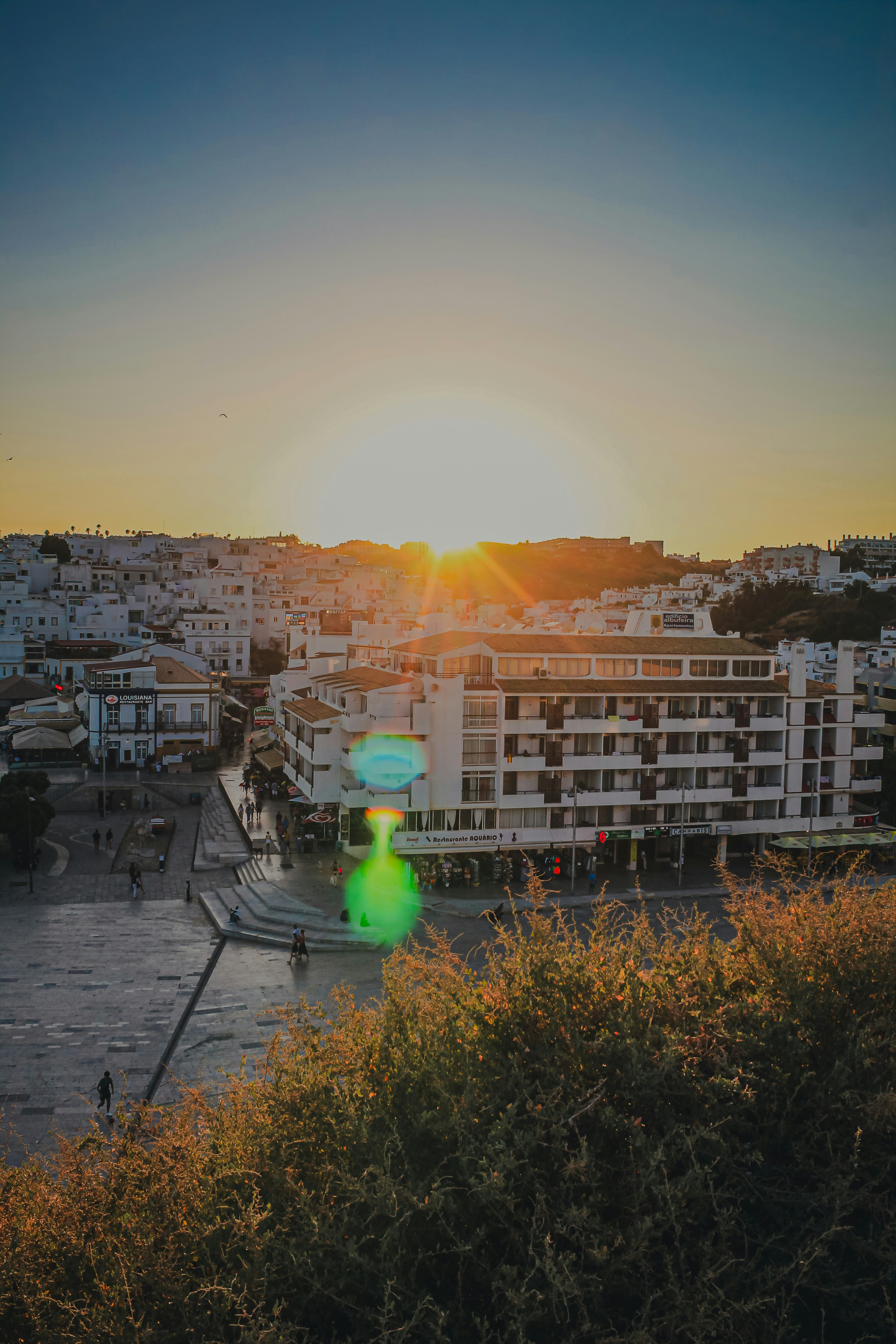 Sunlit Ridge: Cityscape at Sunset with Elevated View and Lens Flare