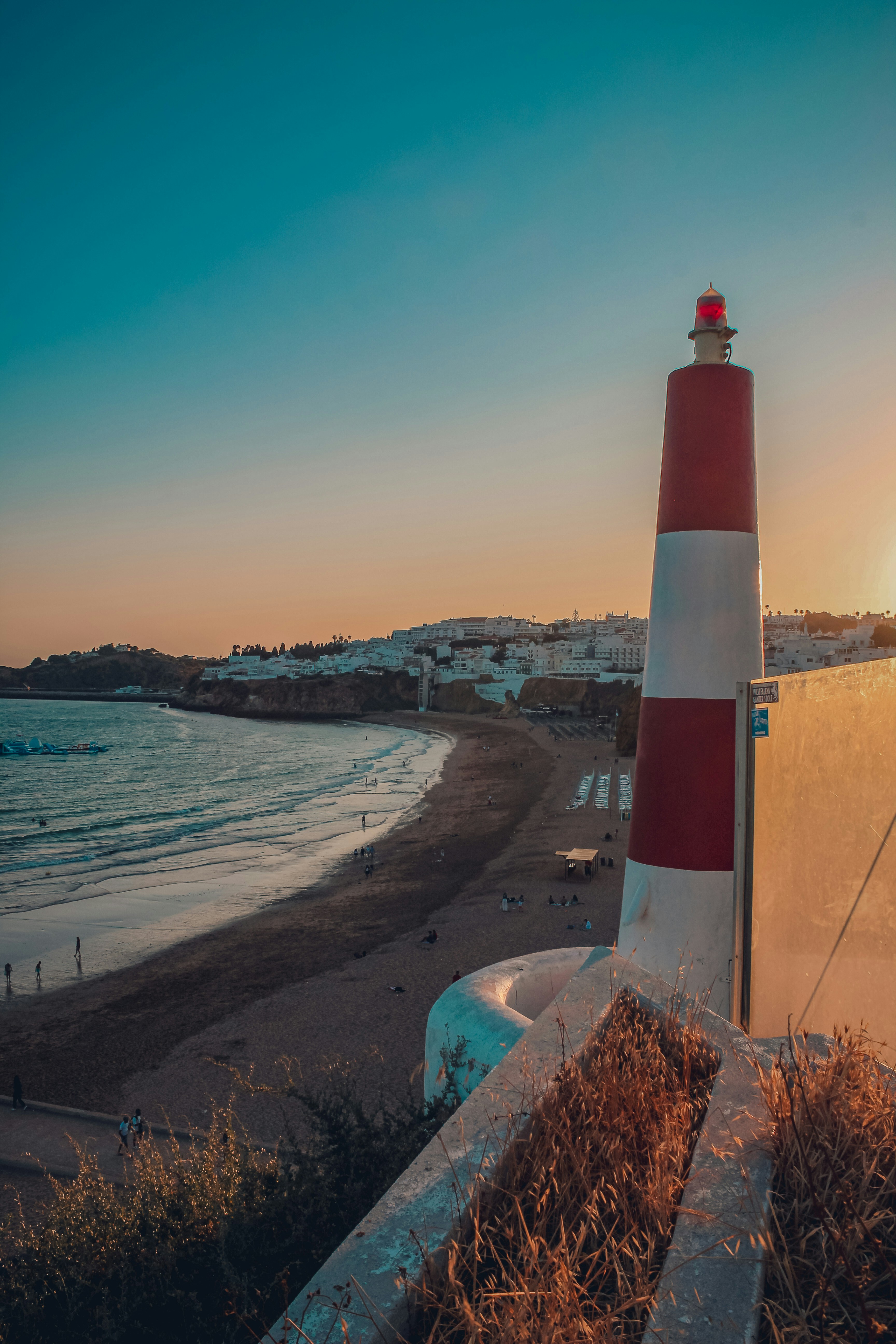 Lighthouse at Dusk: Red and White Sentinel Over Seaside Cliff