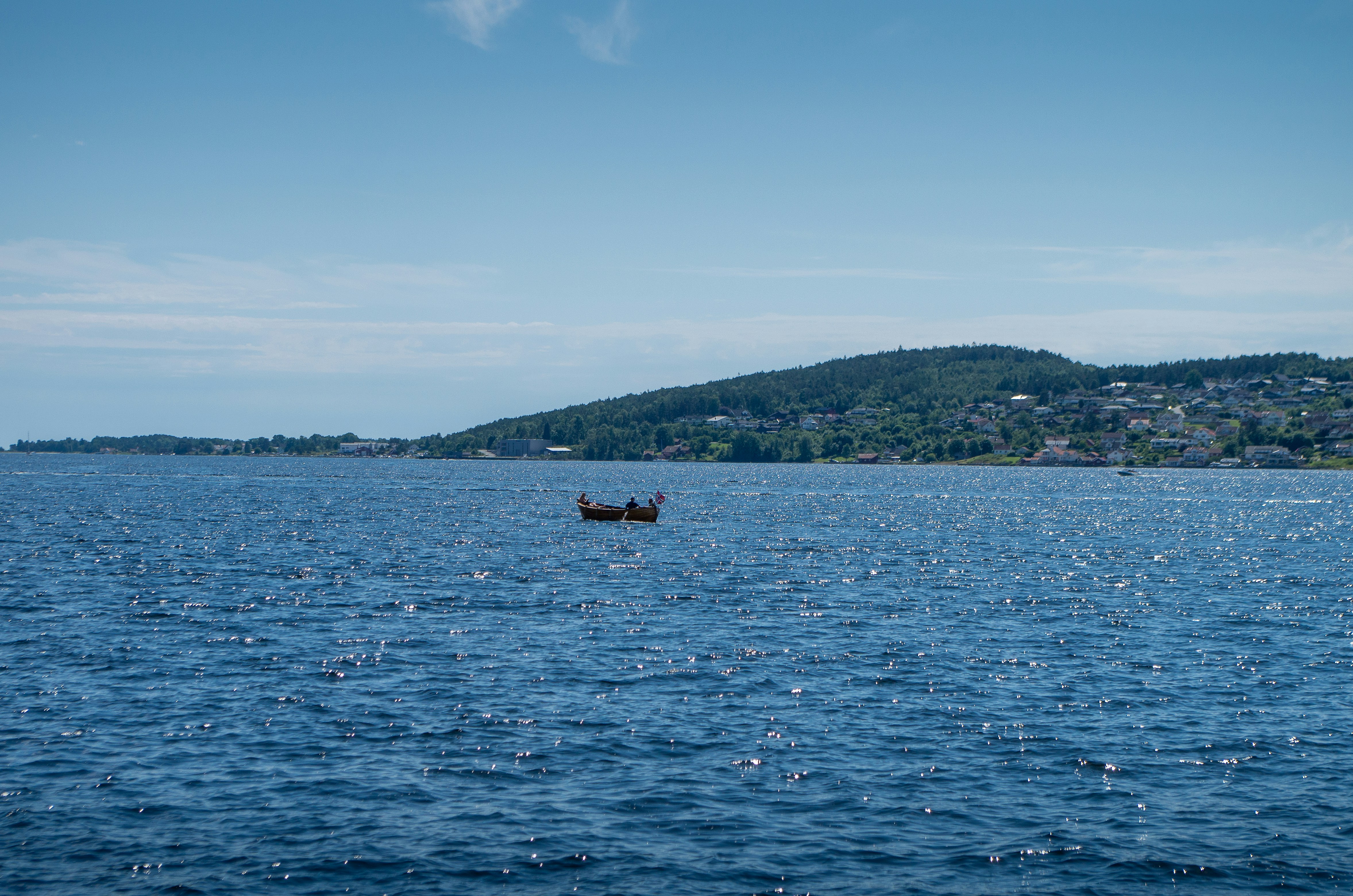 A lone boat on a sunlit sea with a distant shoreline