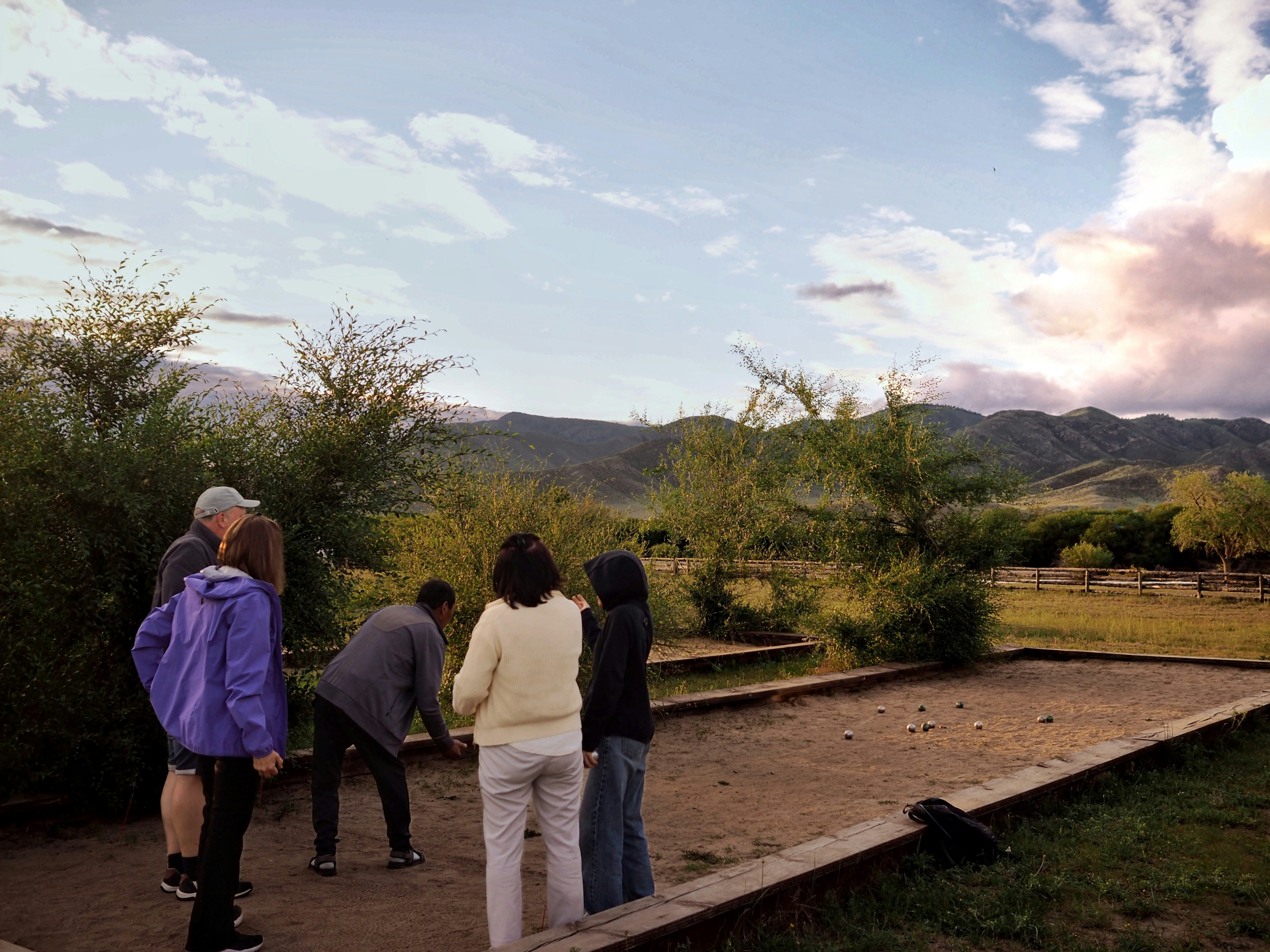 Group of hikers gathers near a wooden overlook in a sunlit hillside park